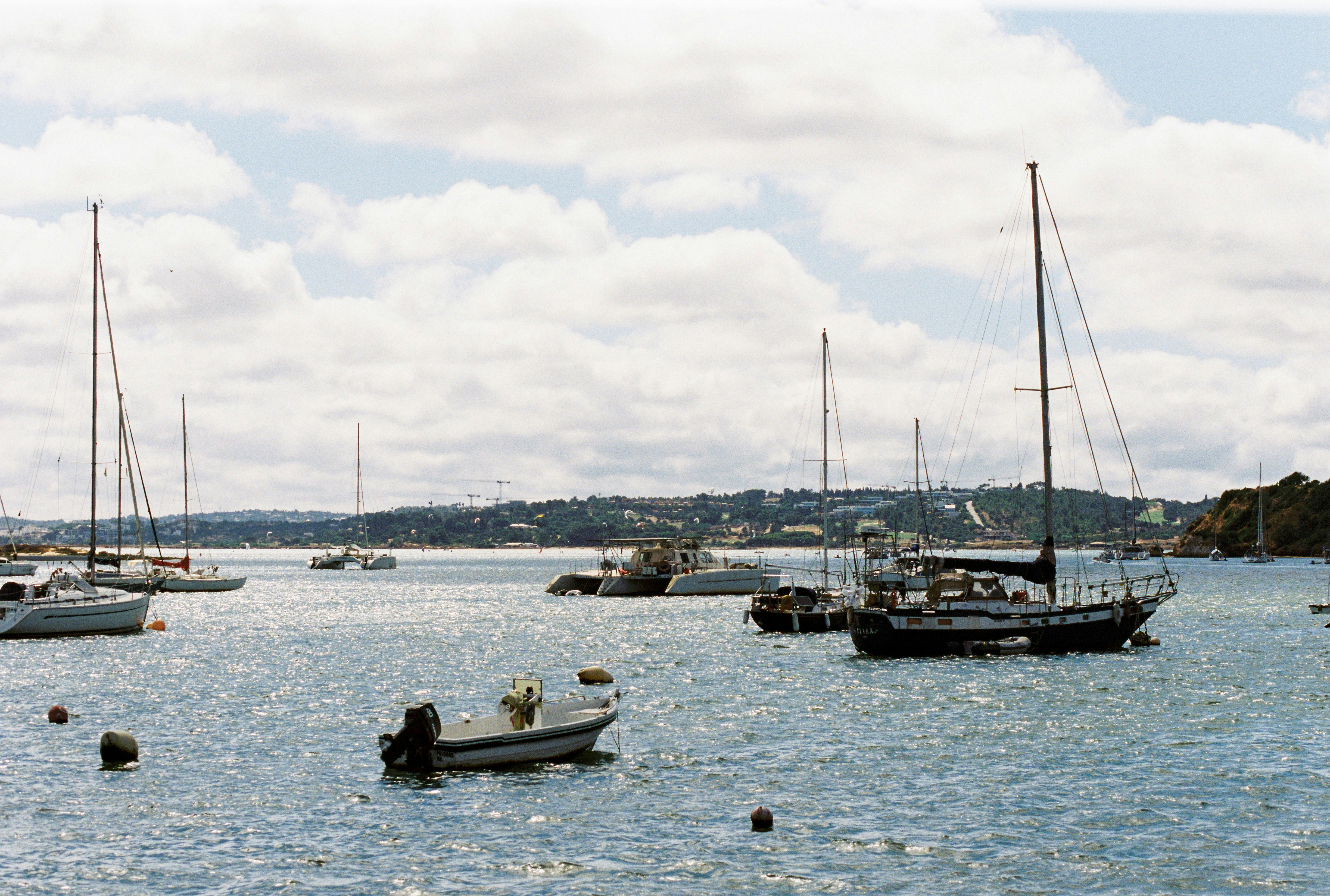 Harbor Quiet: Boats Drift on Sunlit Sea Under Puffy Skies