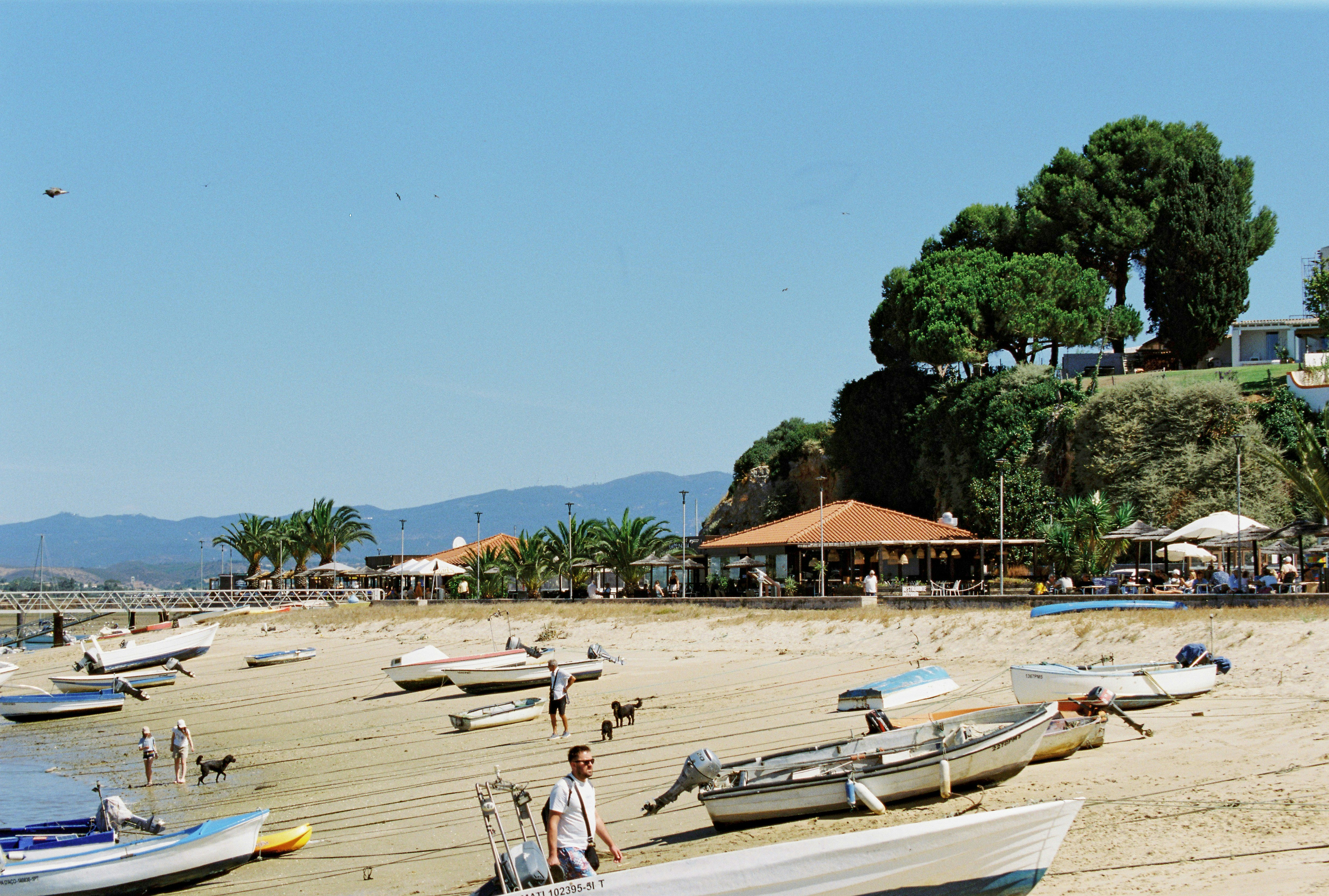 Sunlit Mediterranean Beachfront with Boats and Hilltop Retreat