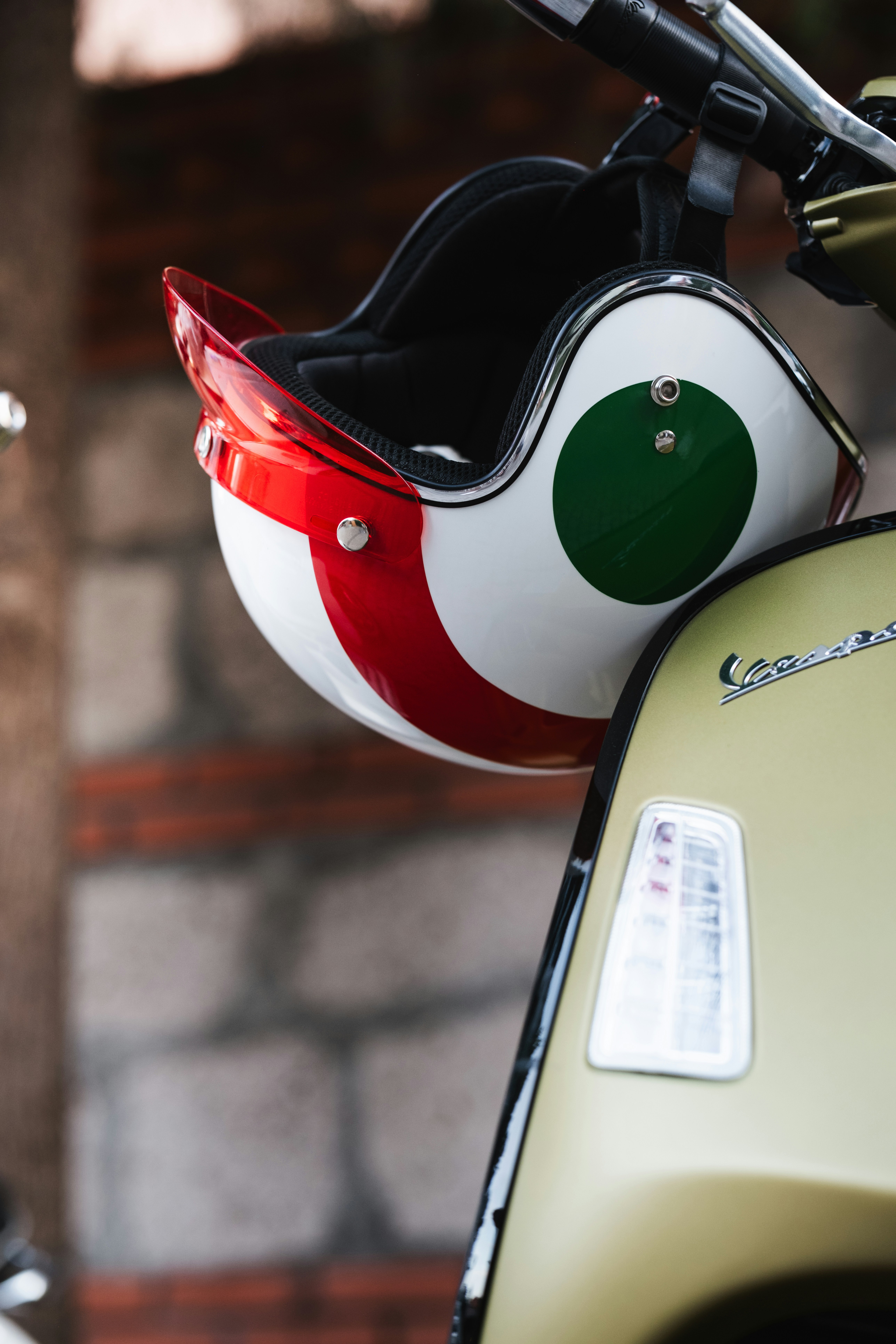 A white helmet with red and green accents hanging on a green scooter