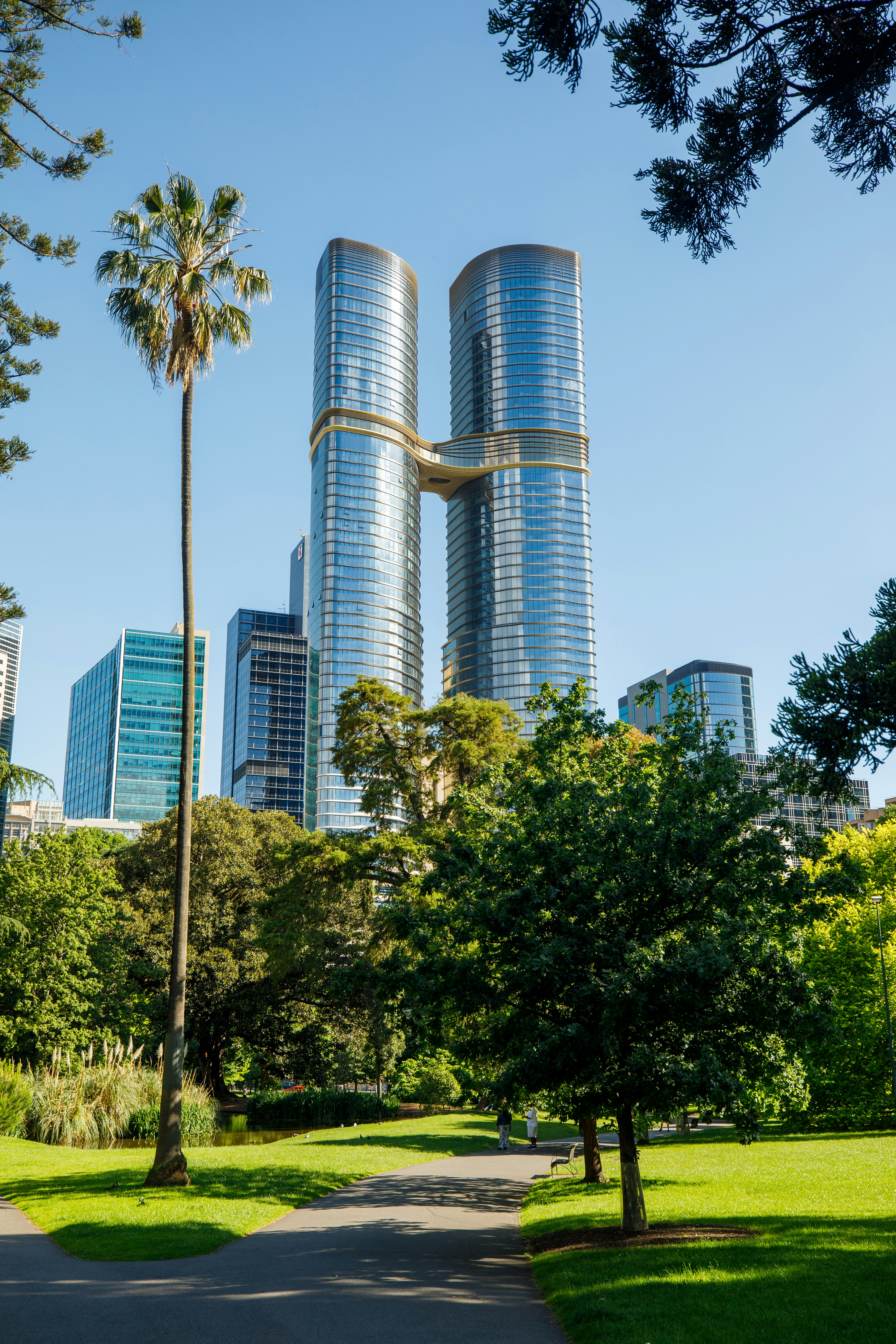Twin Glass Giants Rise Over a Quiet Green Corridor
