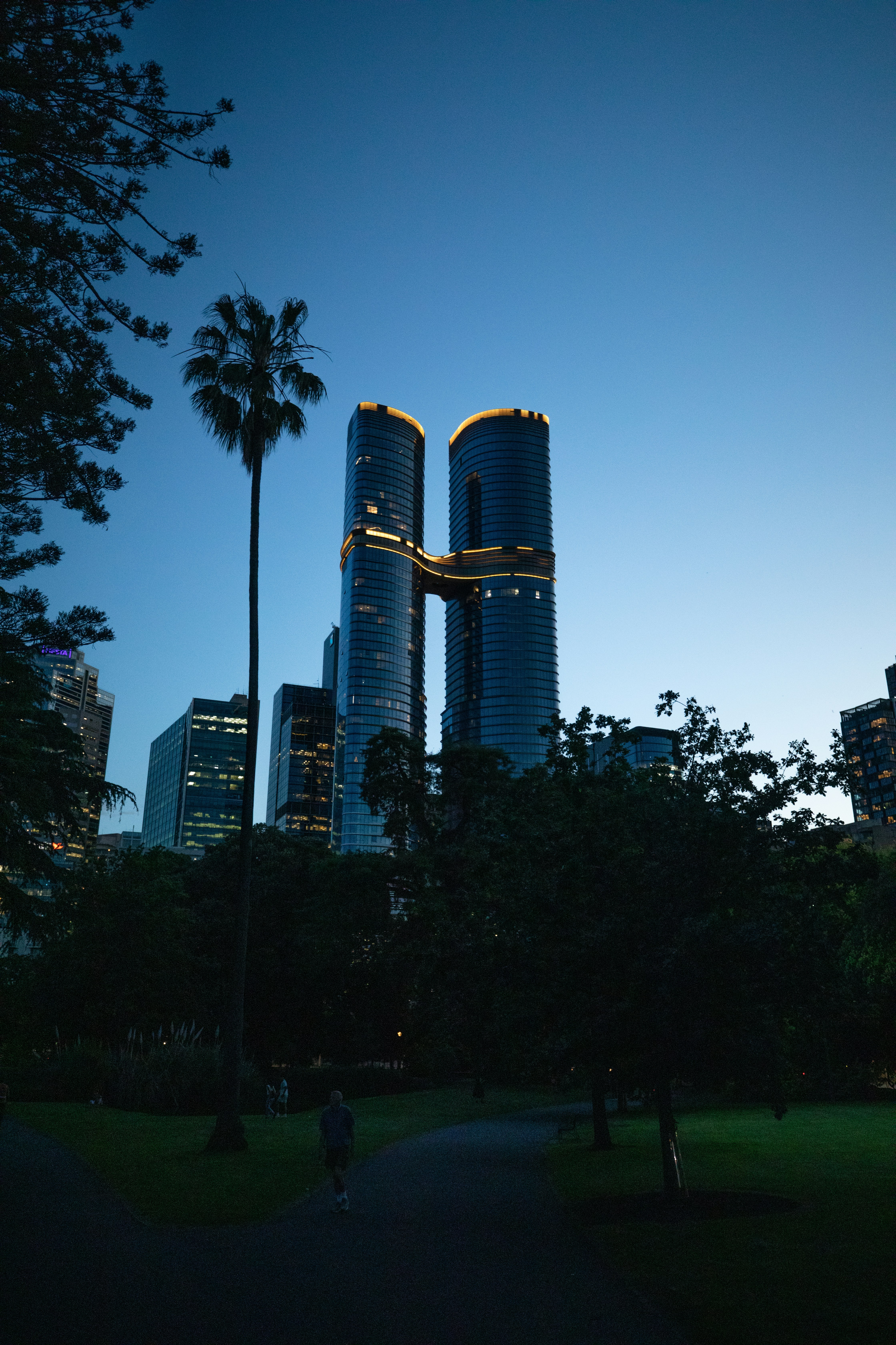 Twin Glass Towers Framed by a Quiet Park at Dusk