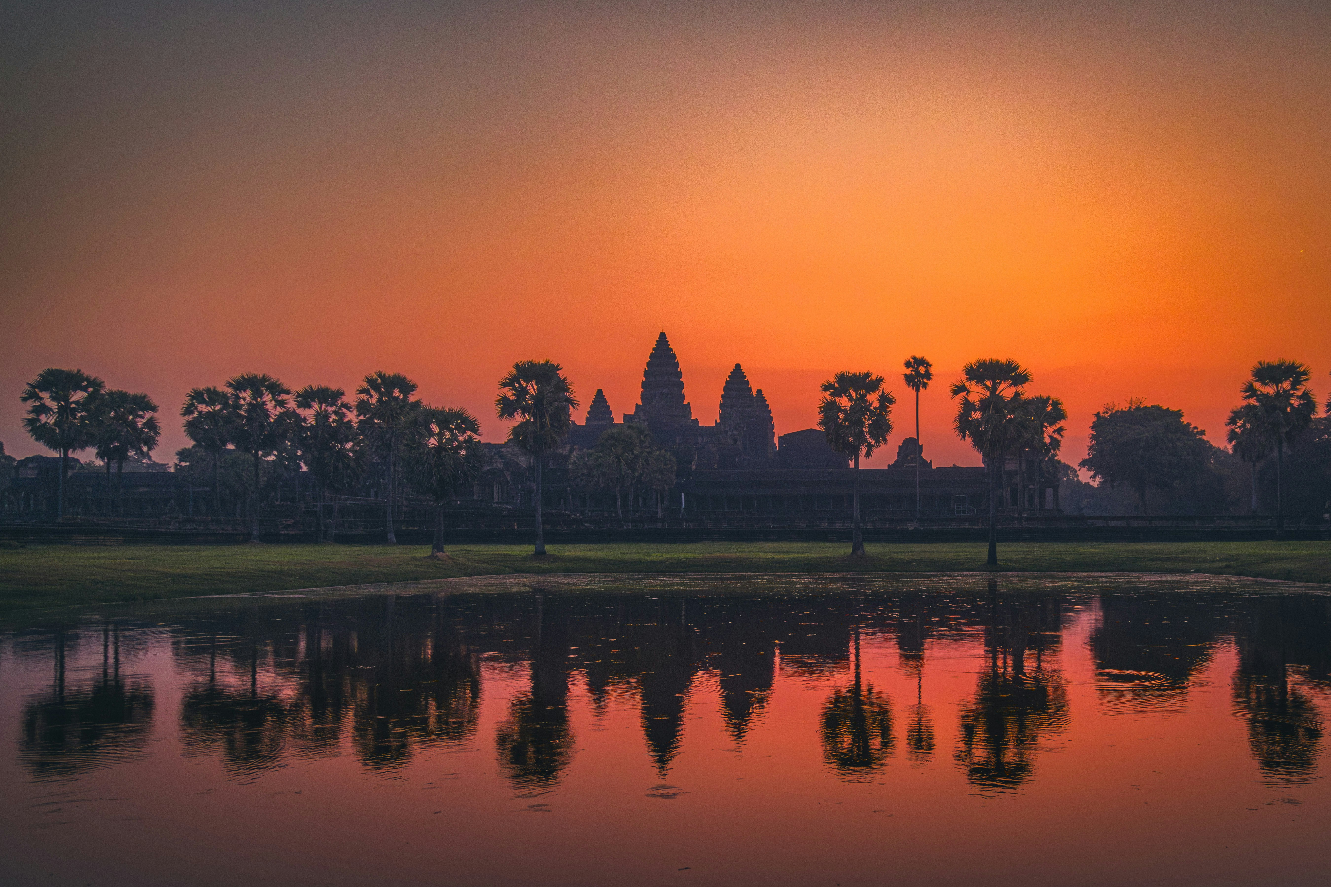 Silhouetted Temple Ridge at Sunset over a Reflective Cambodian Waterway