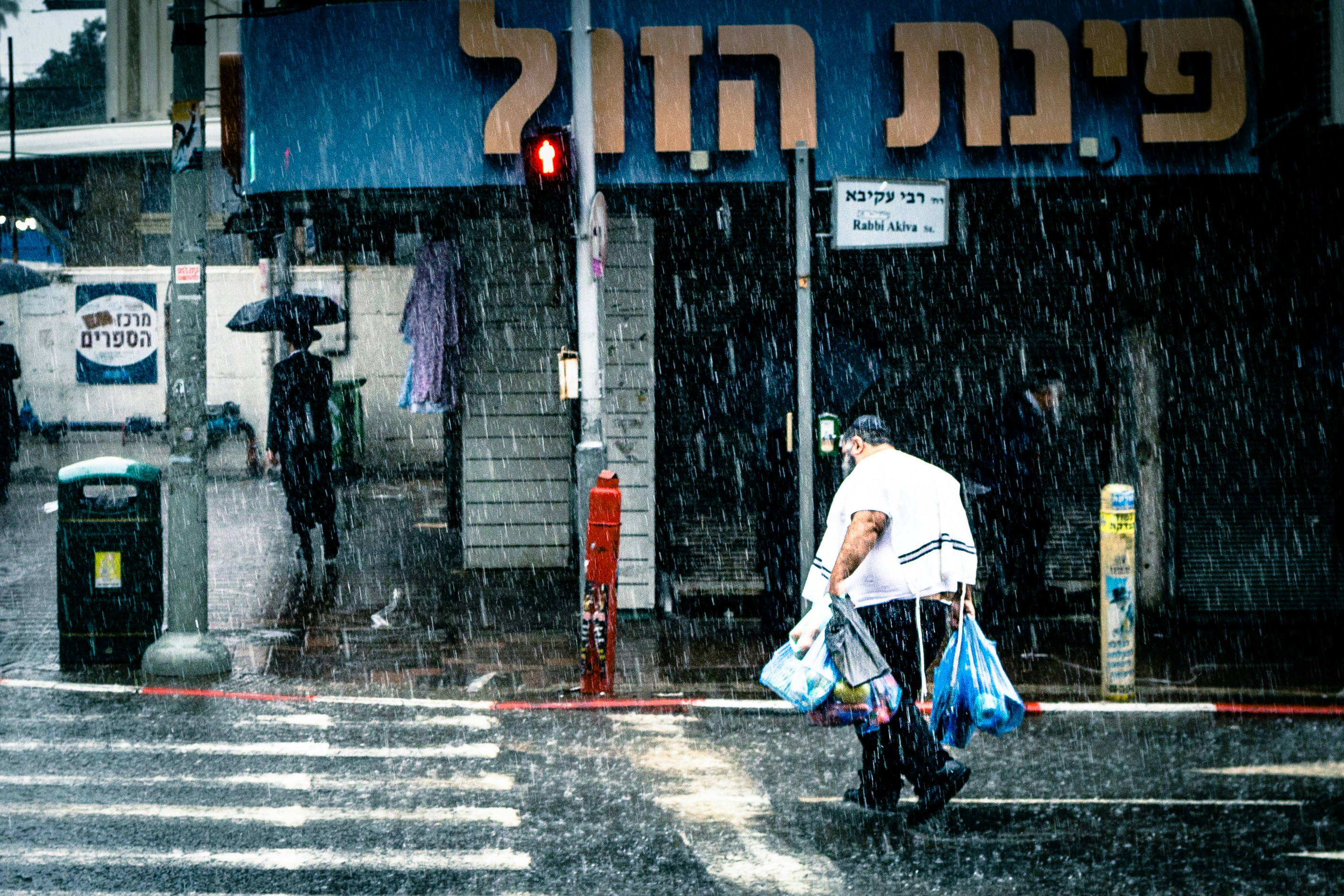 Rainy Street Crossing with a Shrouded Pedestrian
