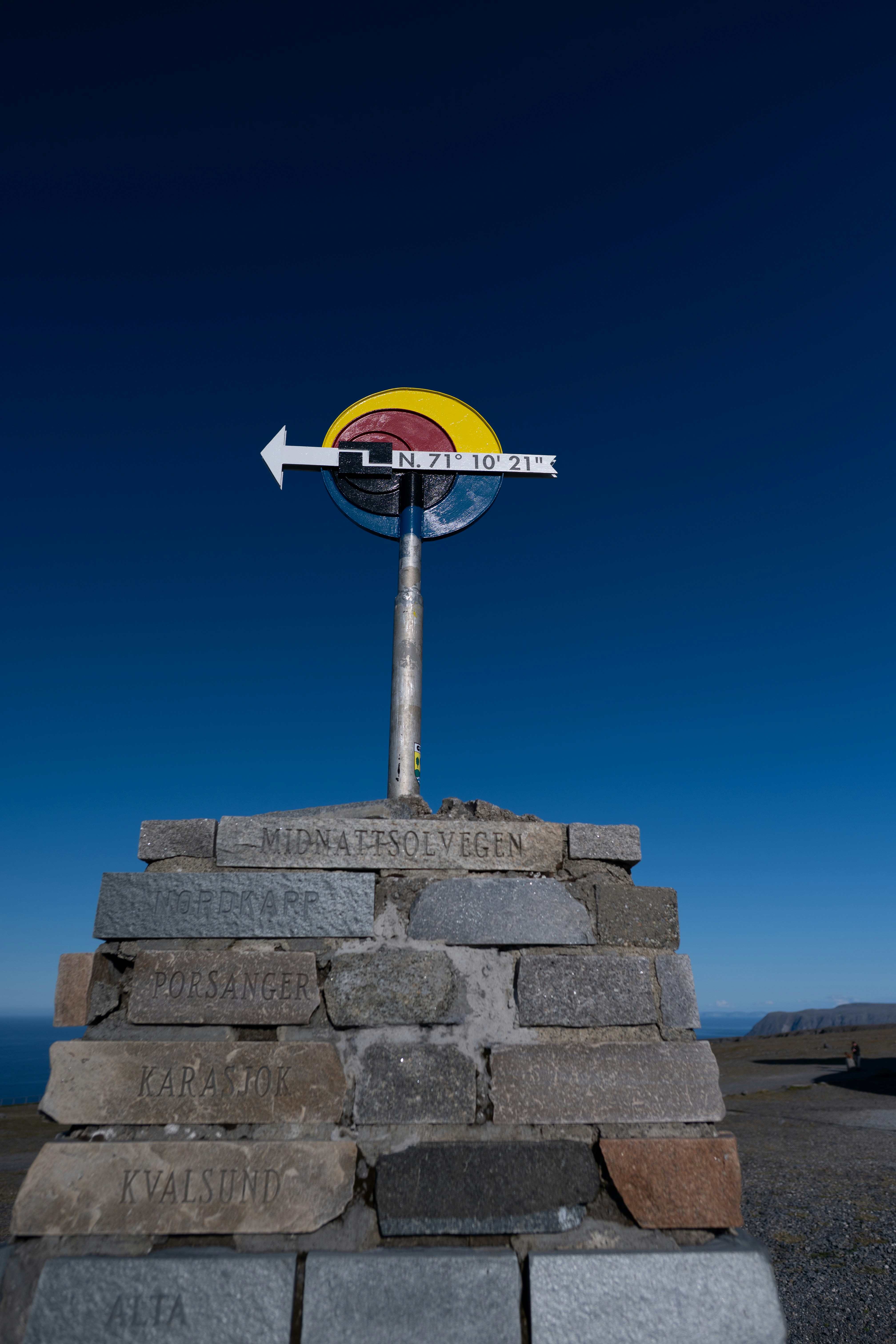 Circle of Coordinates: A Coastal Summit Marker Against a Piercing Sky