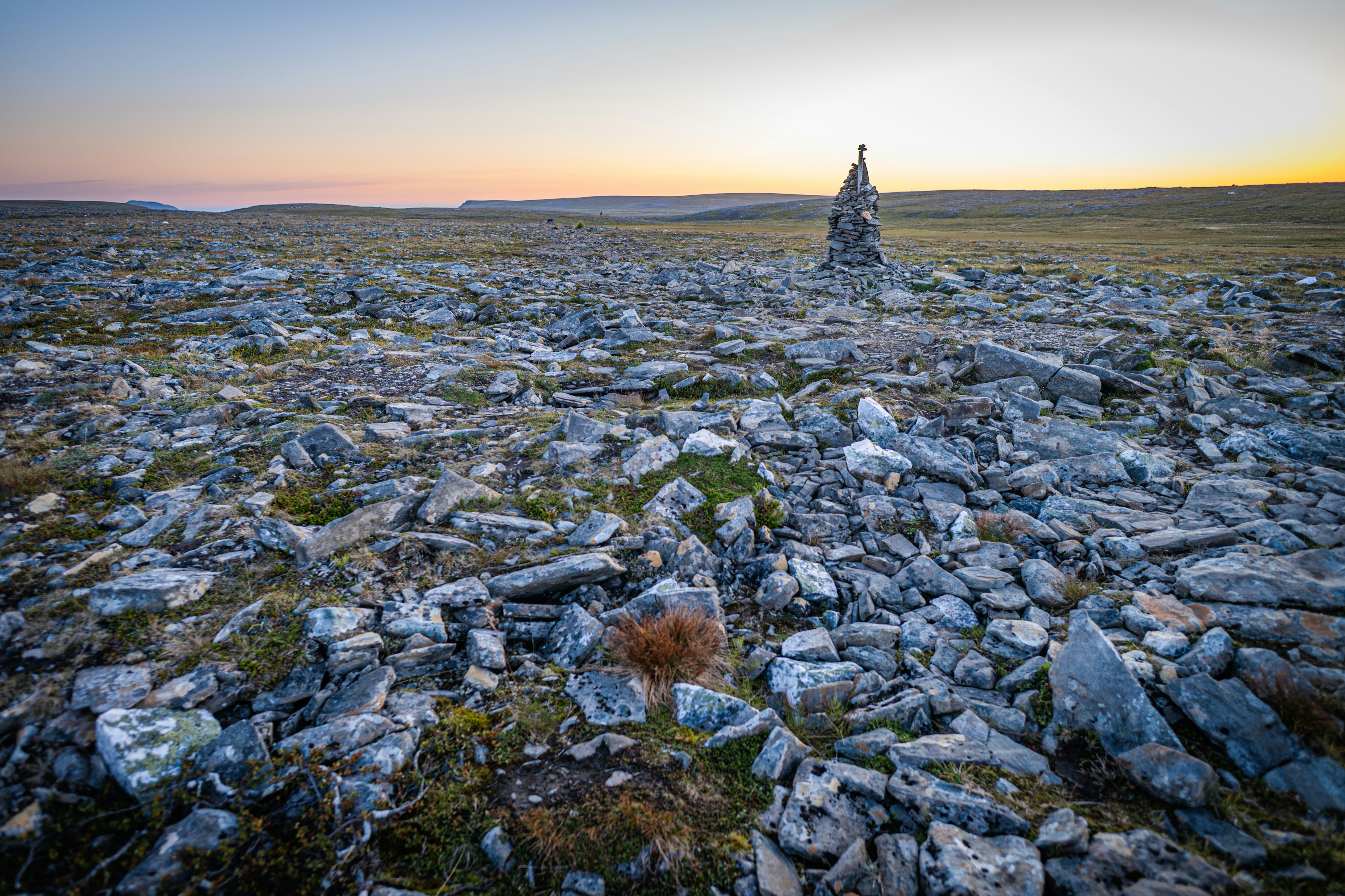 Stone Sentinel at Dusk: A Field of Pebbles and a Lone Cairn