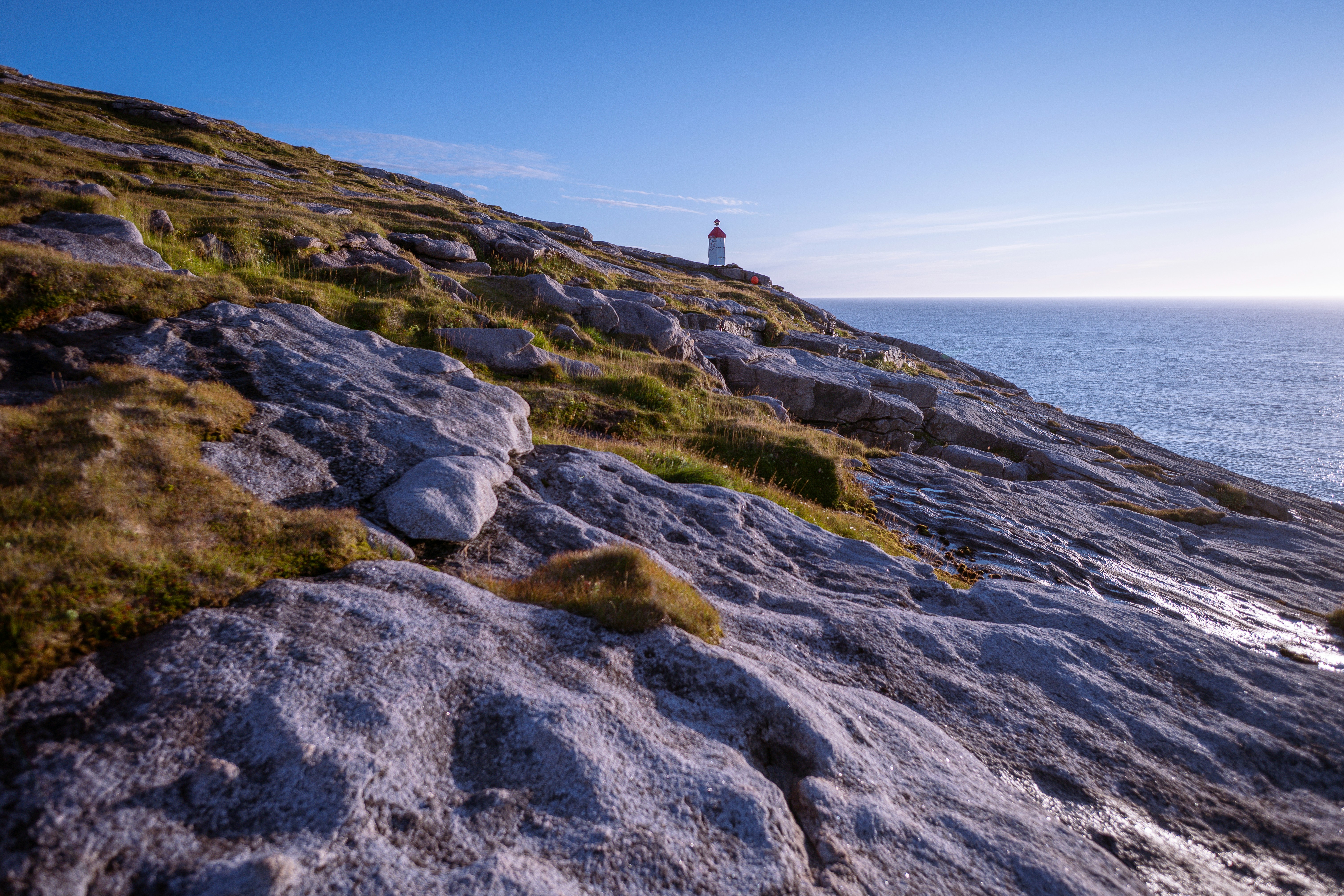 Lighthouse Edge: Rugged Coastline Meeting the Distant Beacon
