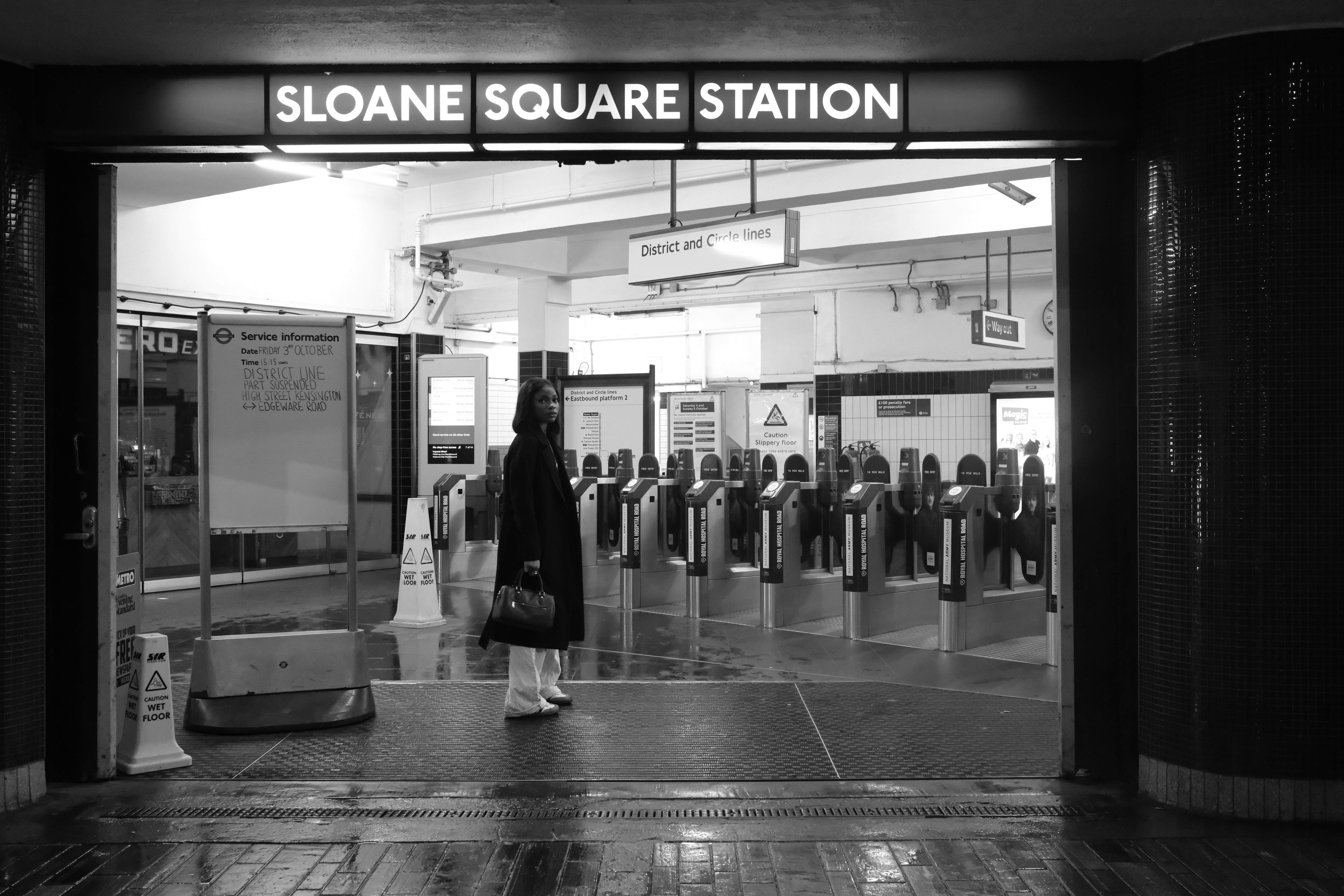 Mid-Entrance Quiet: A Woman Pauses at the Turnstiles