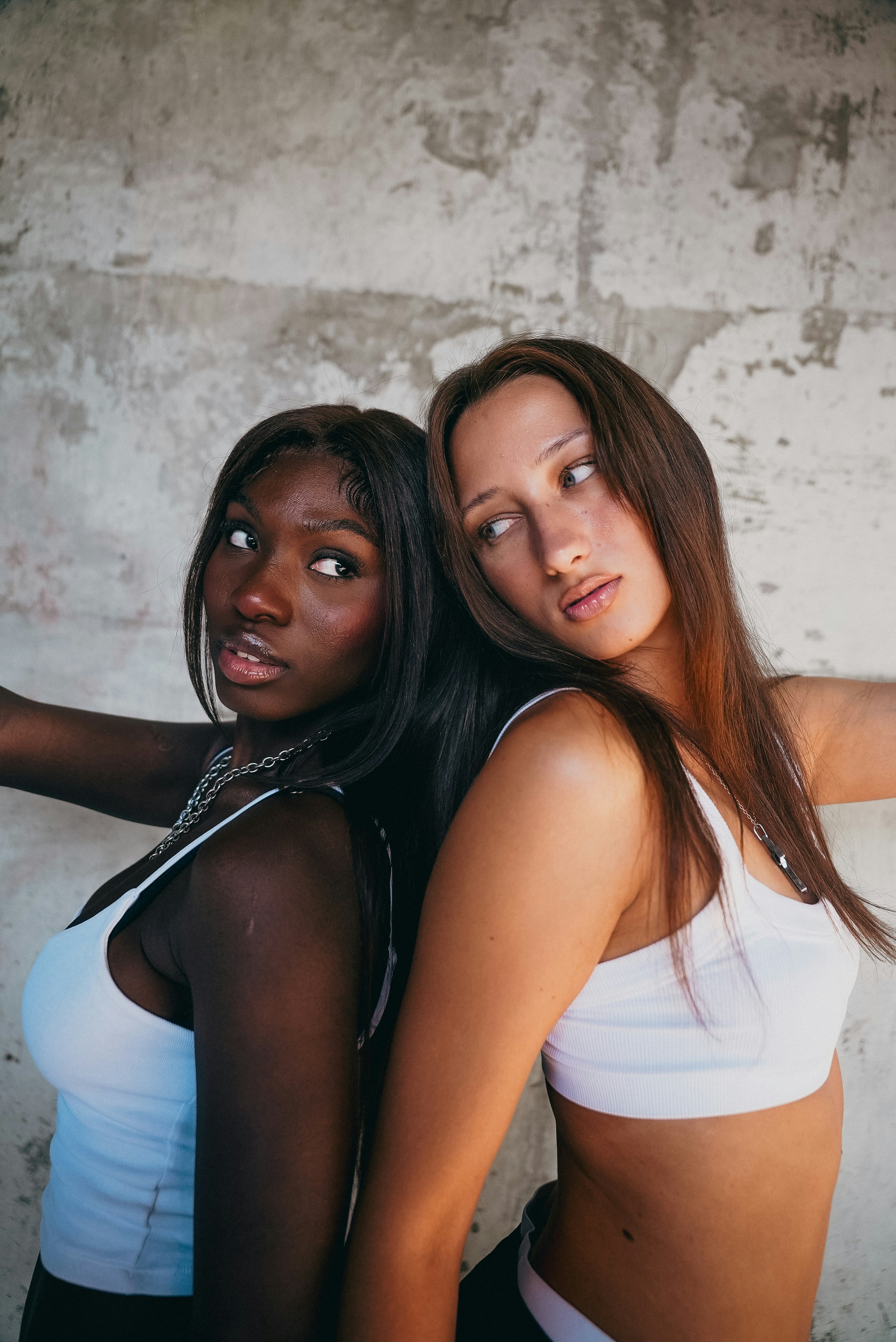 Two Friends Lean Against a Weathered Wall, Their Faces Intertwined