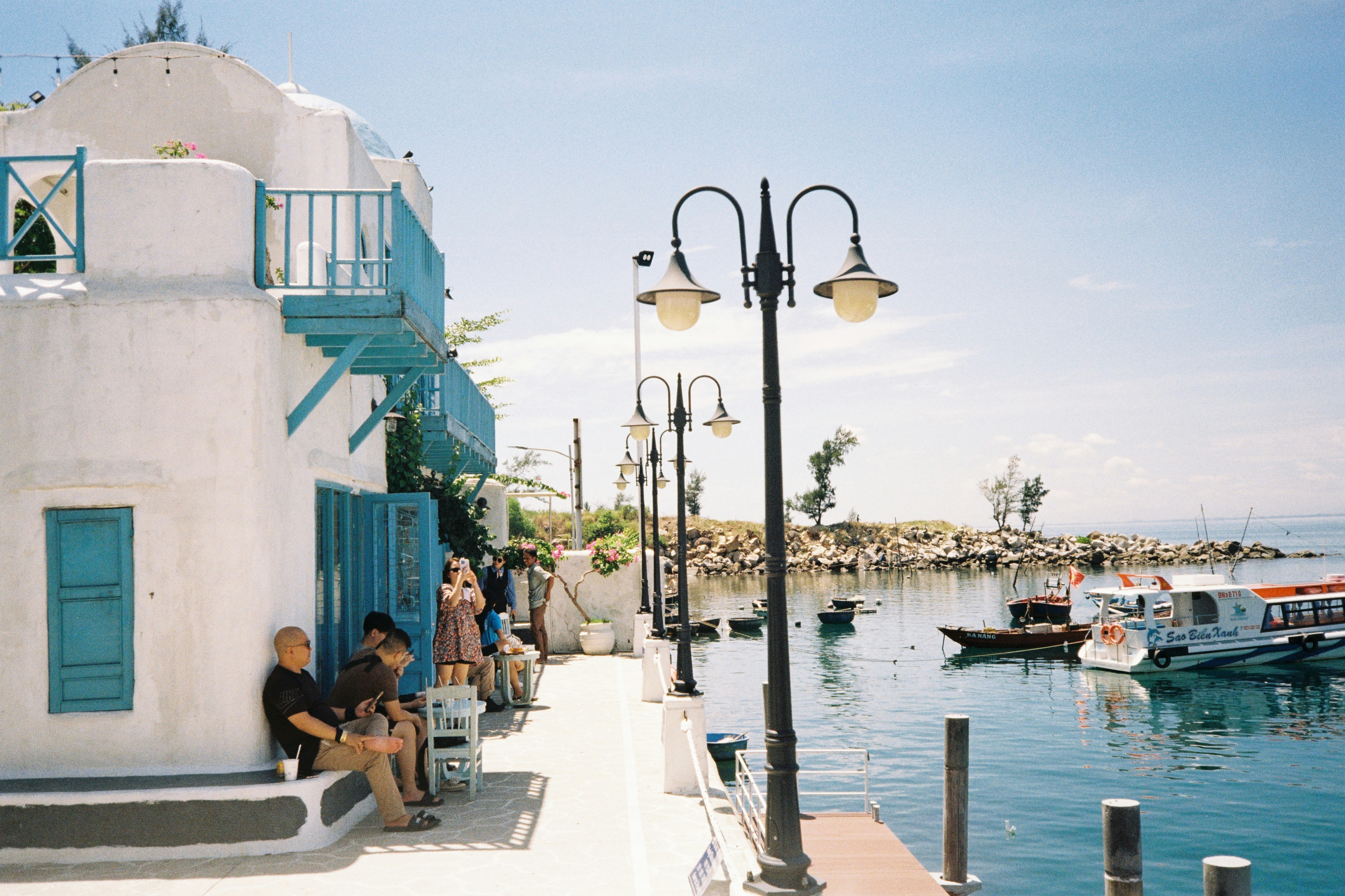Sunlit quay of a Cycladic harbor with pastel facades and calm turquoise water