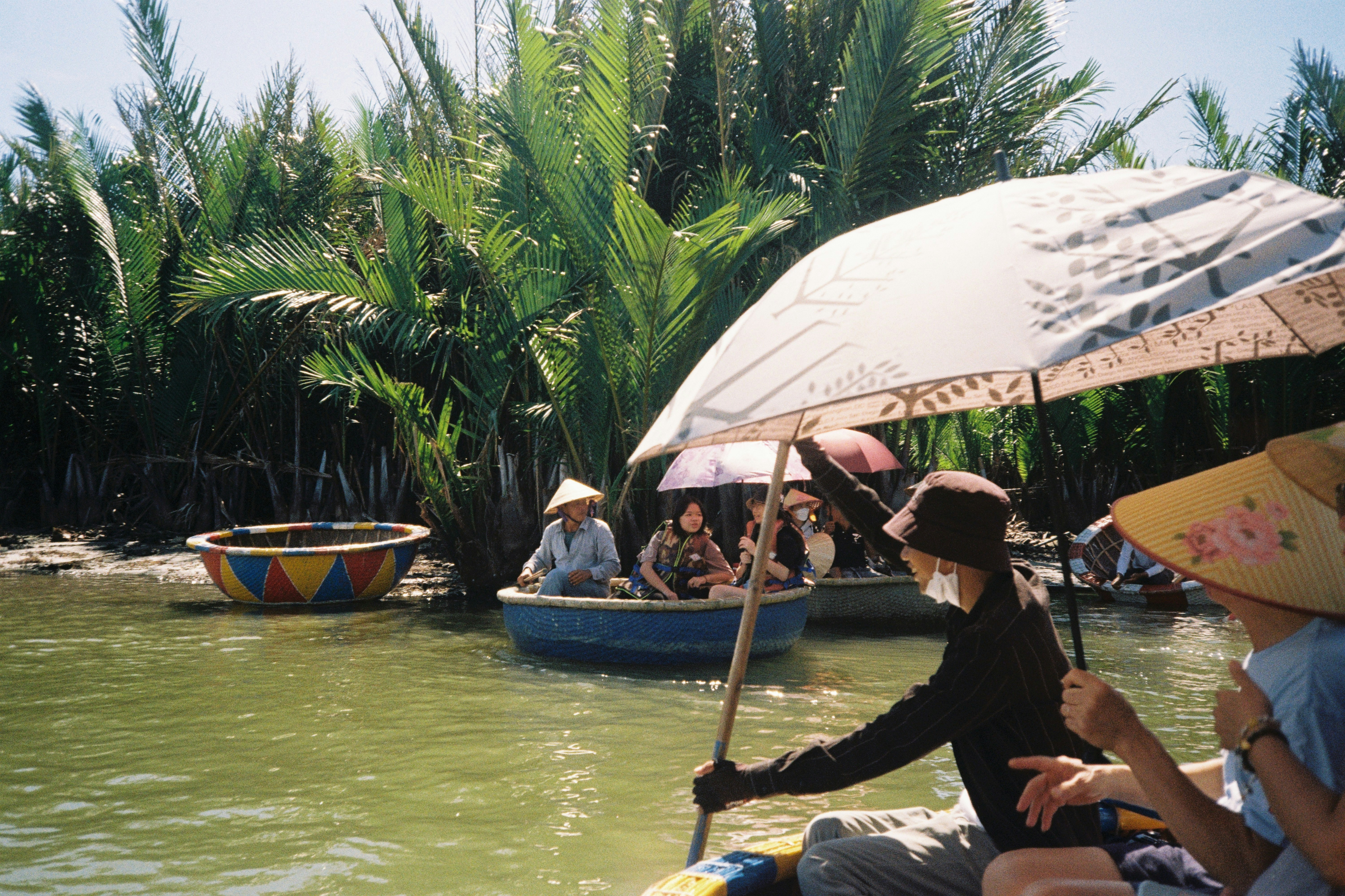 Umbrellaed Ferry: People on a Calm Waterway Amid Palm Fronds