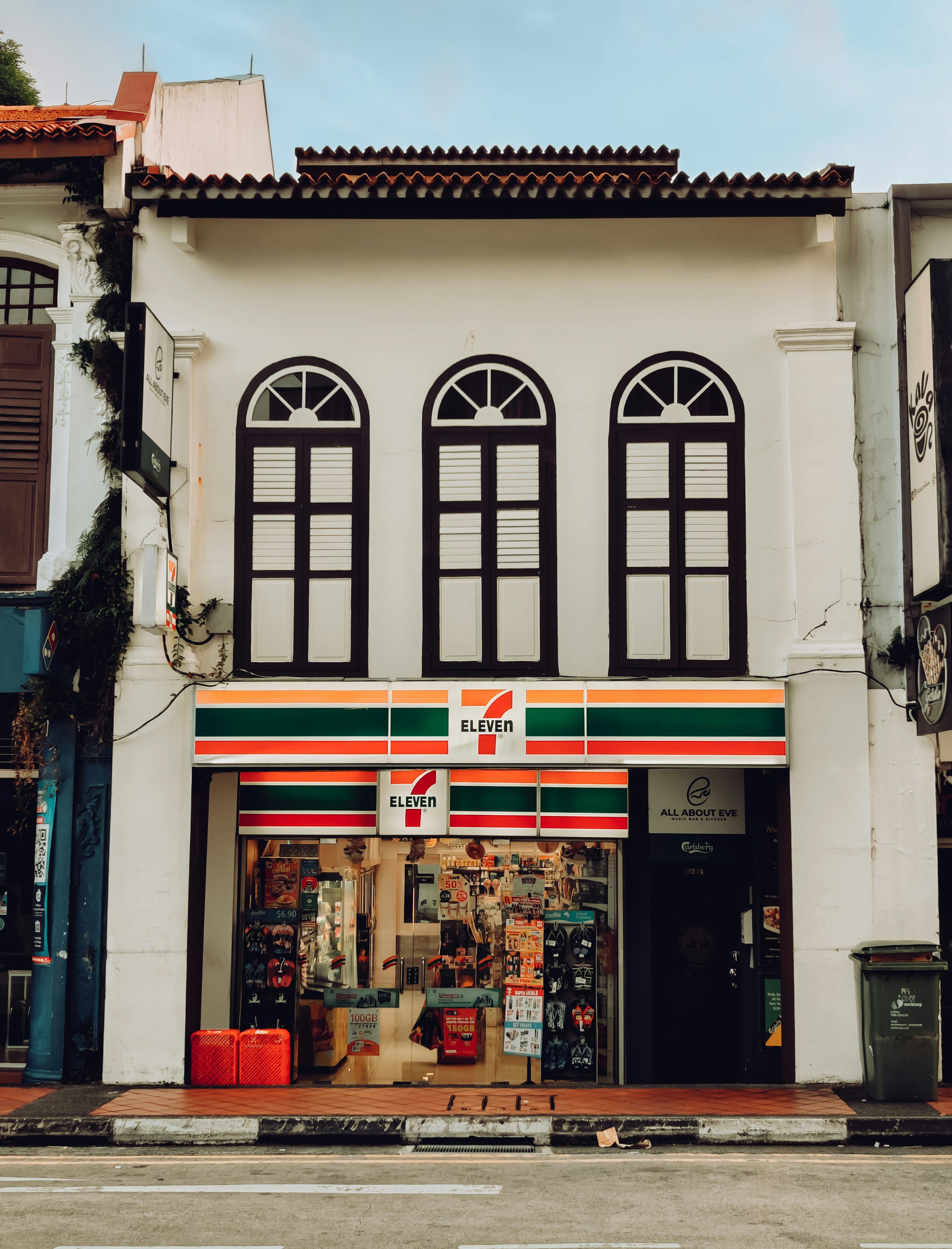 Colorful 7-Eleven storefront with arched second-floor windows and a quiet street façade.