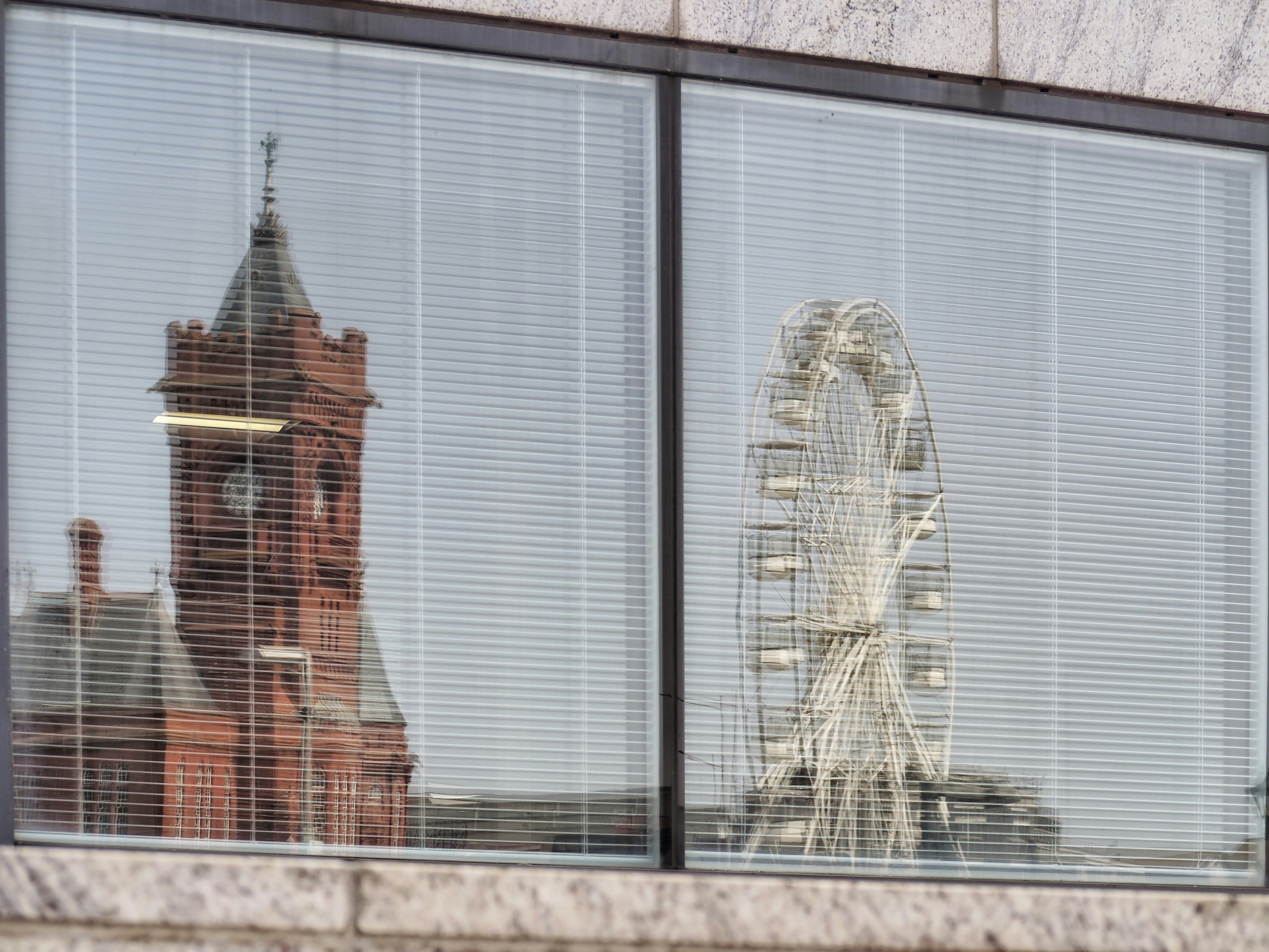 Reflections of a City: Clock Tower and Ferris Wheel through Glass