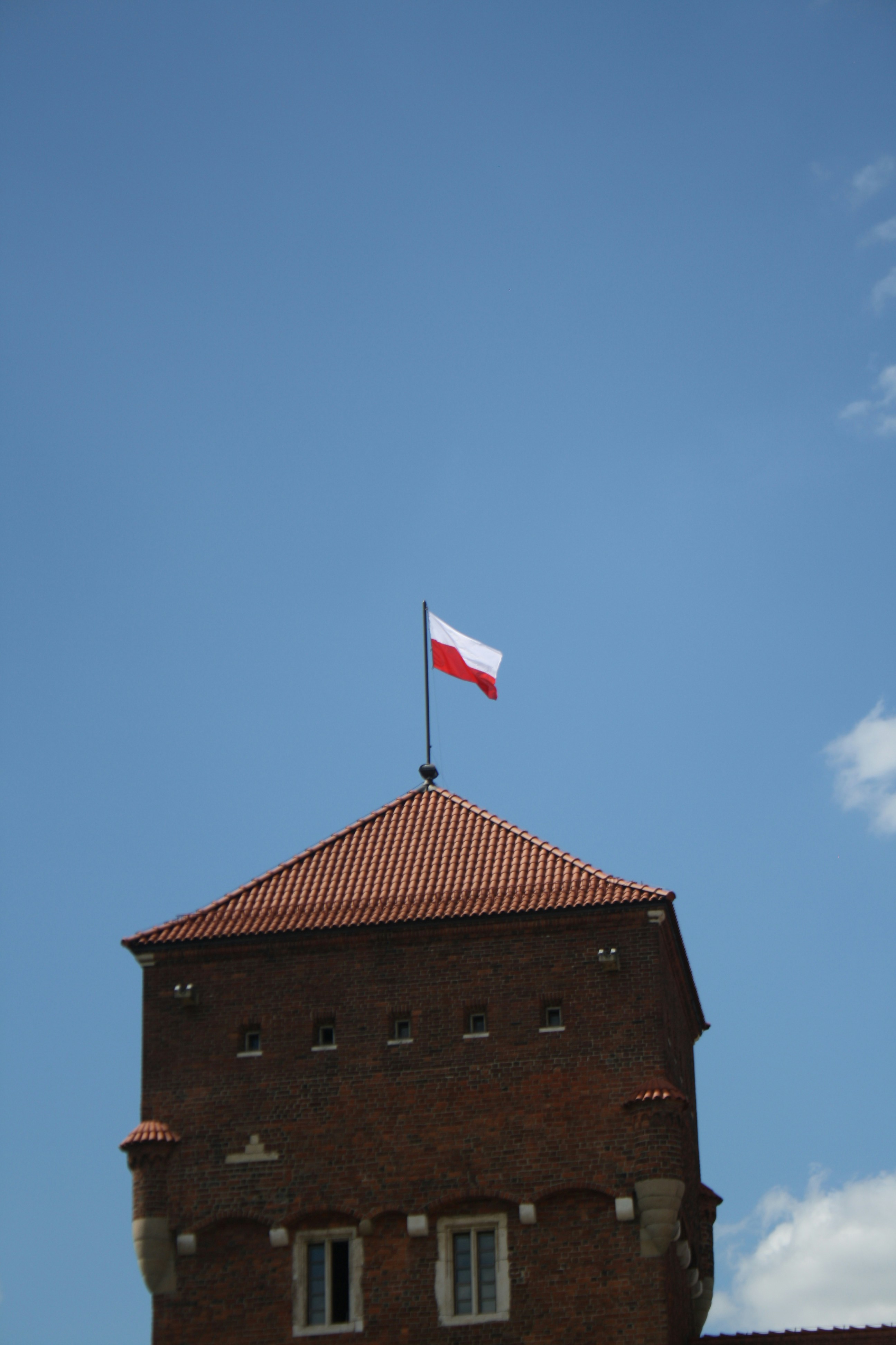 Flag atop brick fortress under a clear blue sky