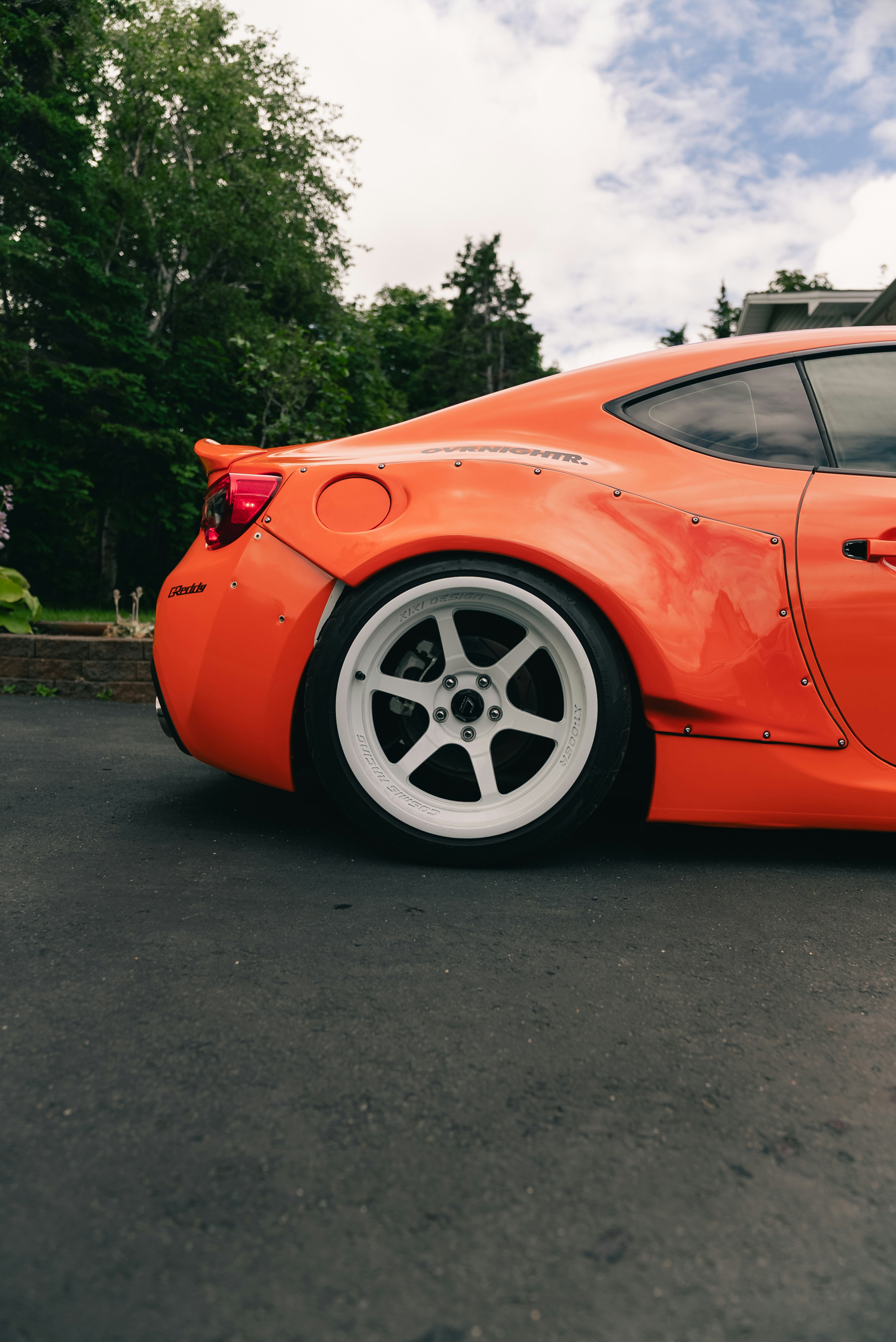 Orange racer: a close-up of a modified sports car tail and rear wheel