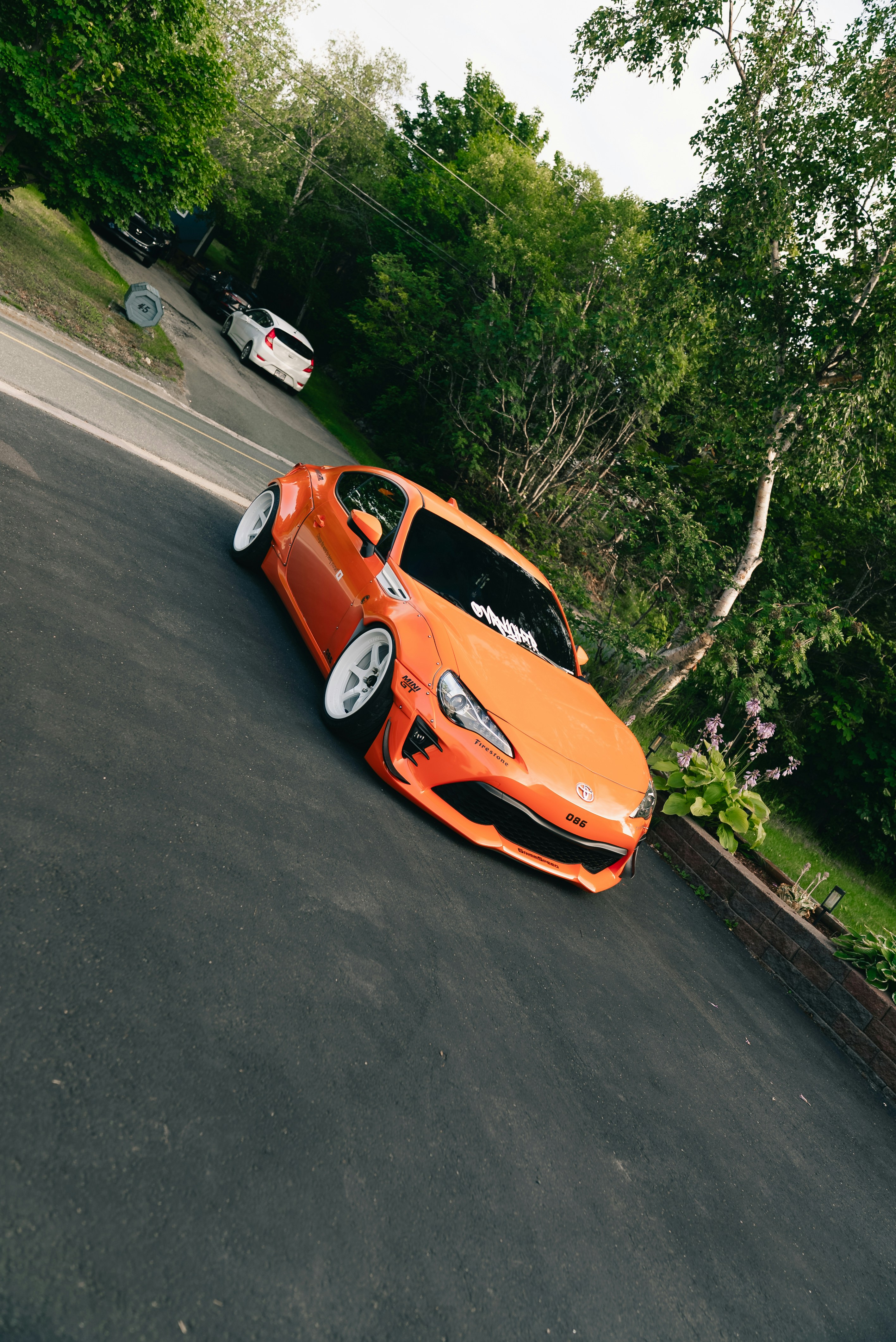 Orange Prelude: A low-slung coupe rests at an angle on a suburban driveway