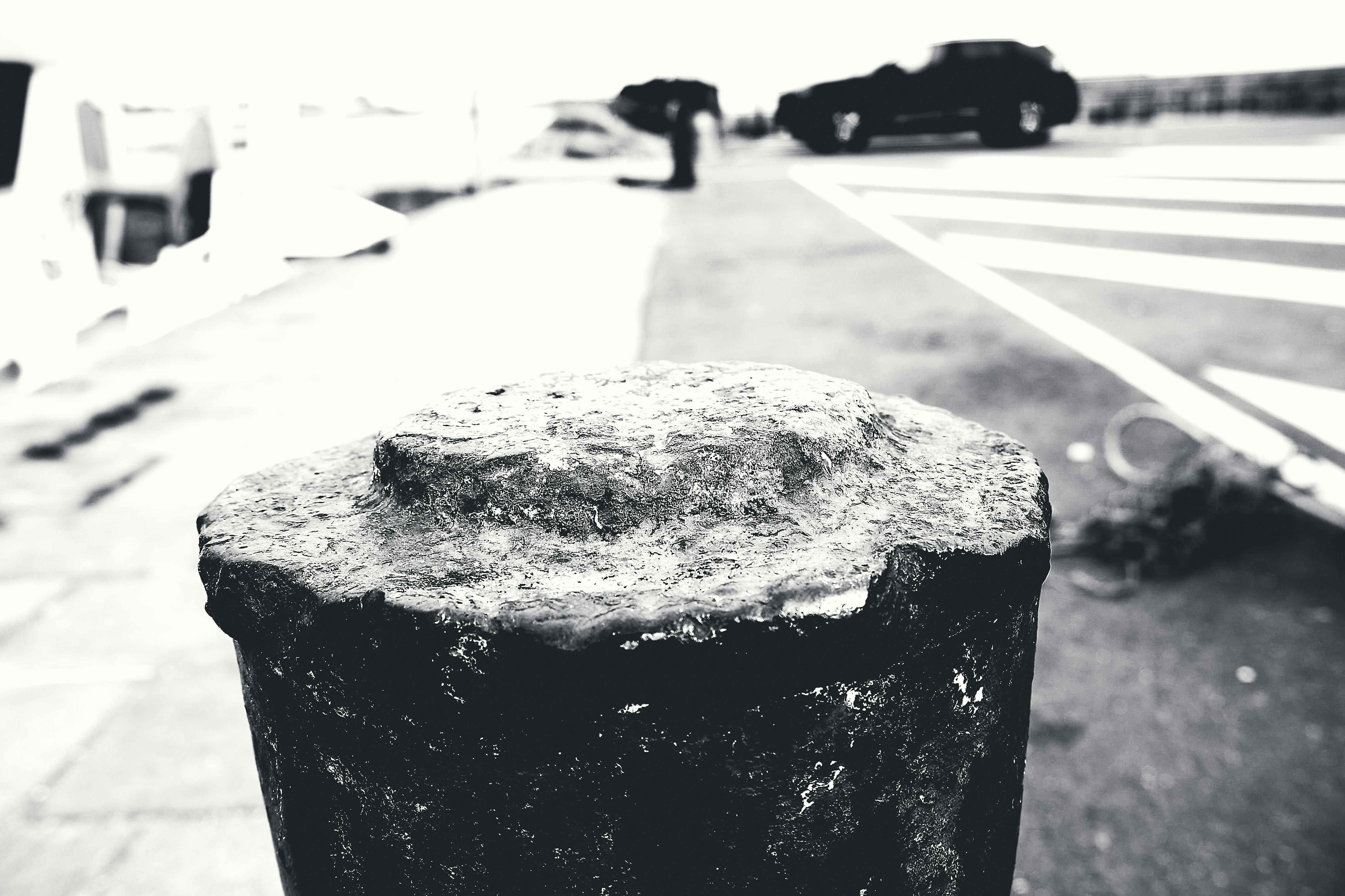 Weathered street bollard: a stark foreground against a blurred urban backdrop