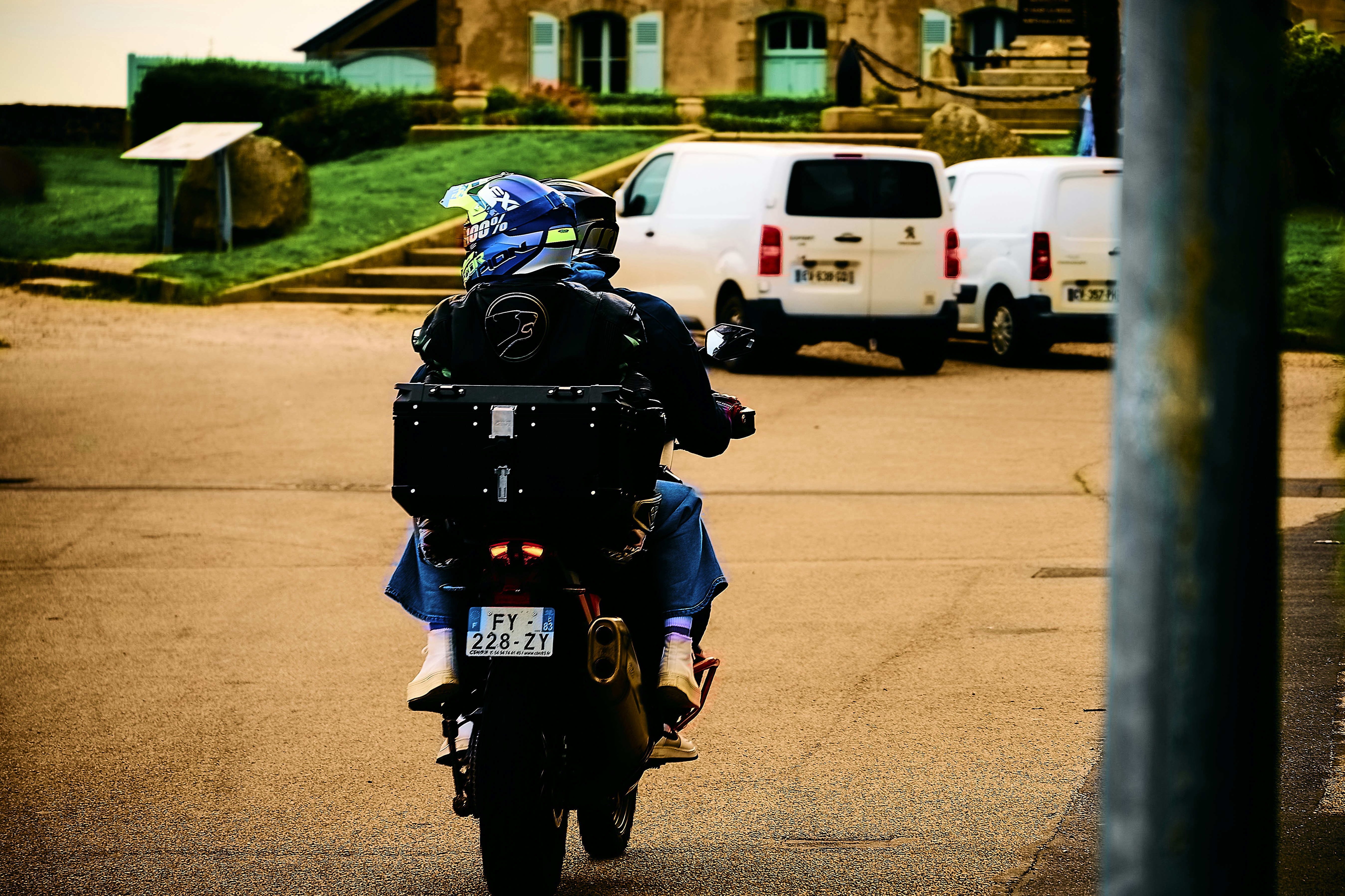 Rear-view Ride: Rider in Black Jacket Heads Toward a Quiet Parking Lot
