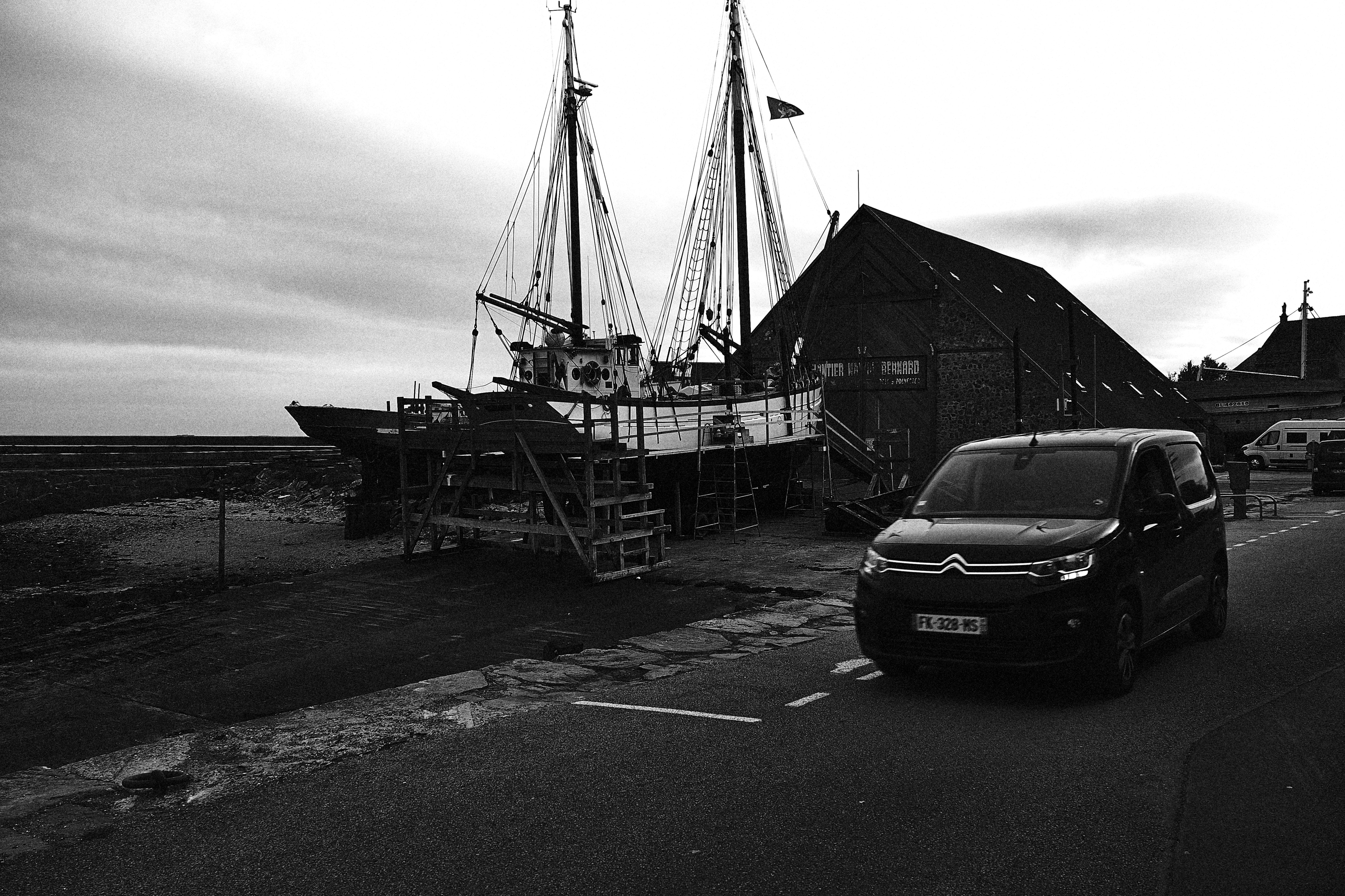 Harbor Gatekeeper: Docked Sails and City Street in Monochrome