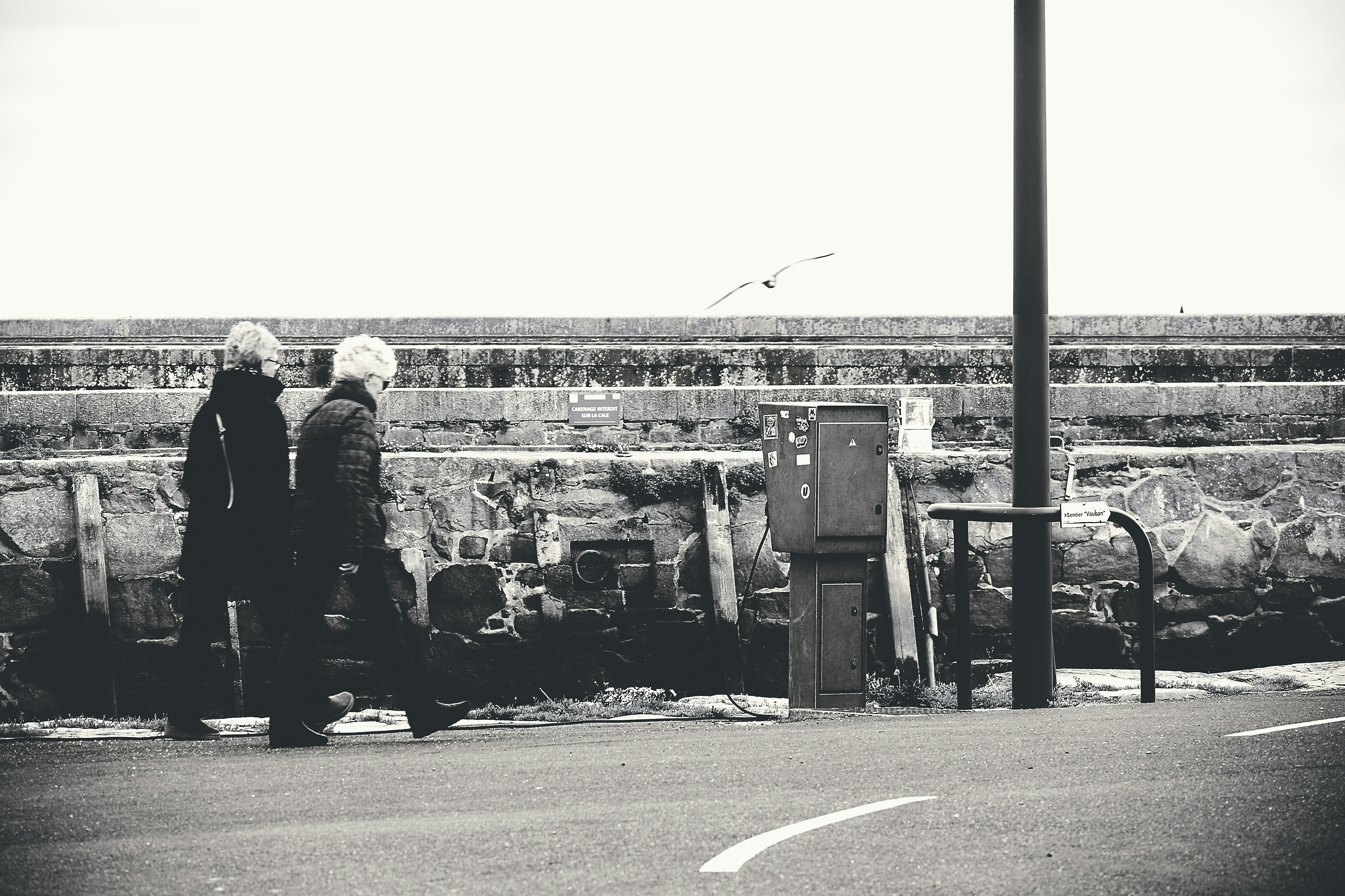 Quiet Street Portrait: Two Elderly Figures Along a Weathered Quay