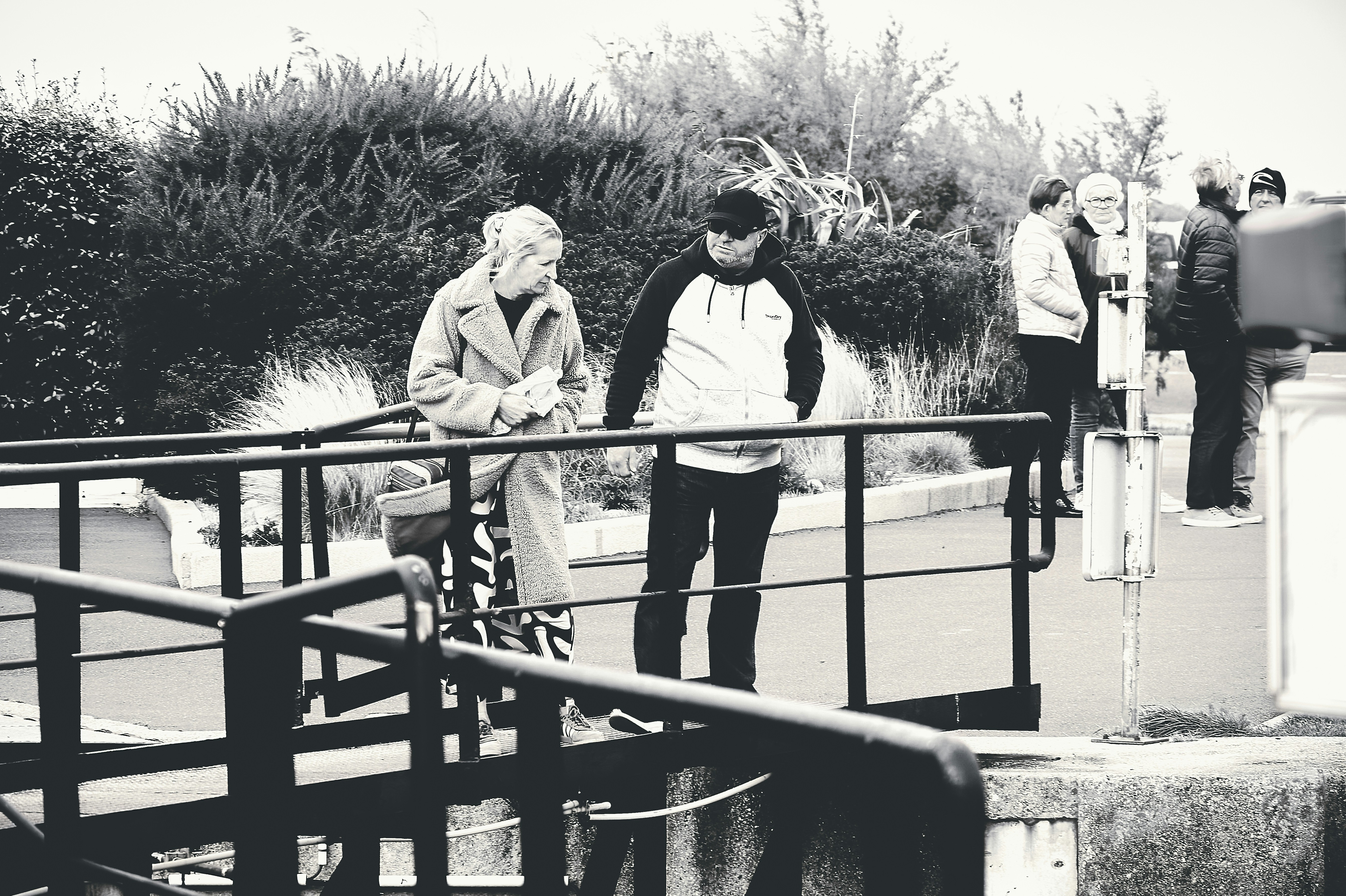 Two pedestrians at a bus stop fade into a quiet riverside scene