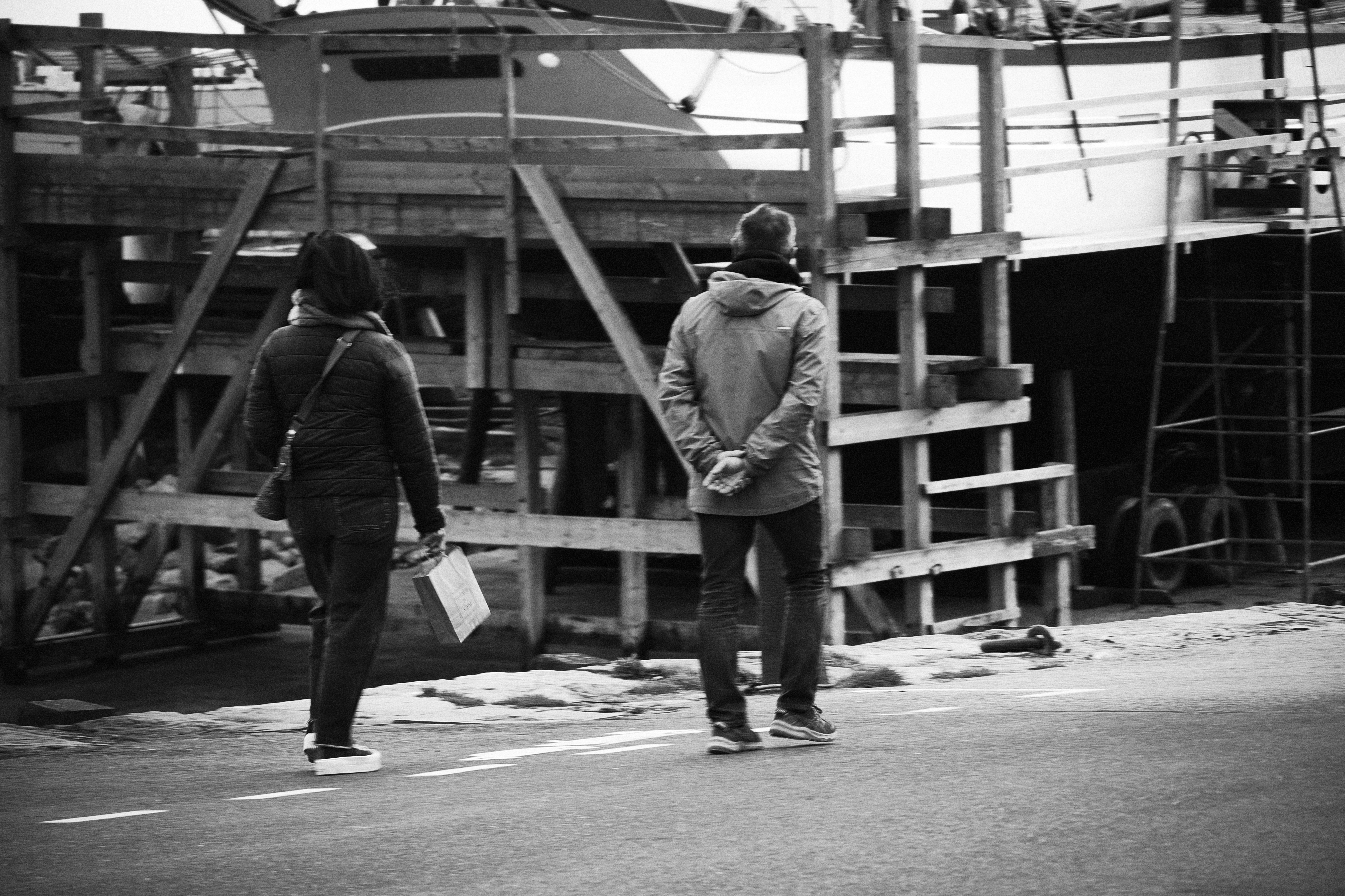 Two observers at a shipyard: silhouettes against a docked hull