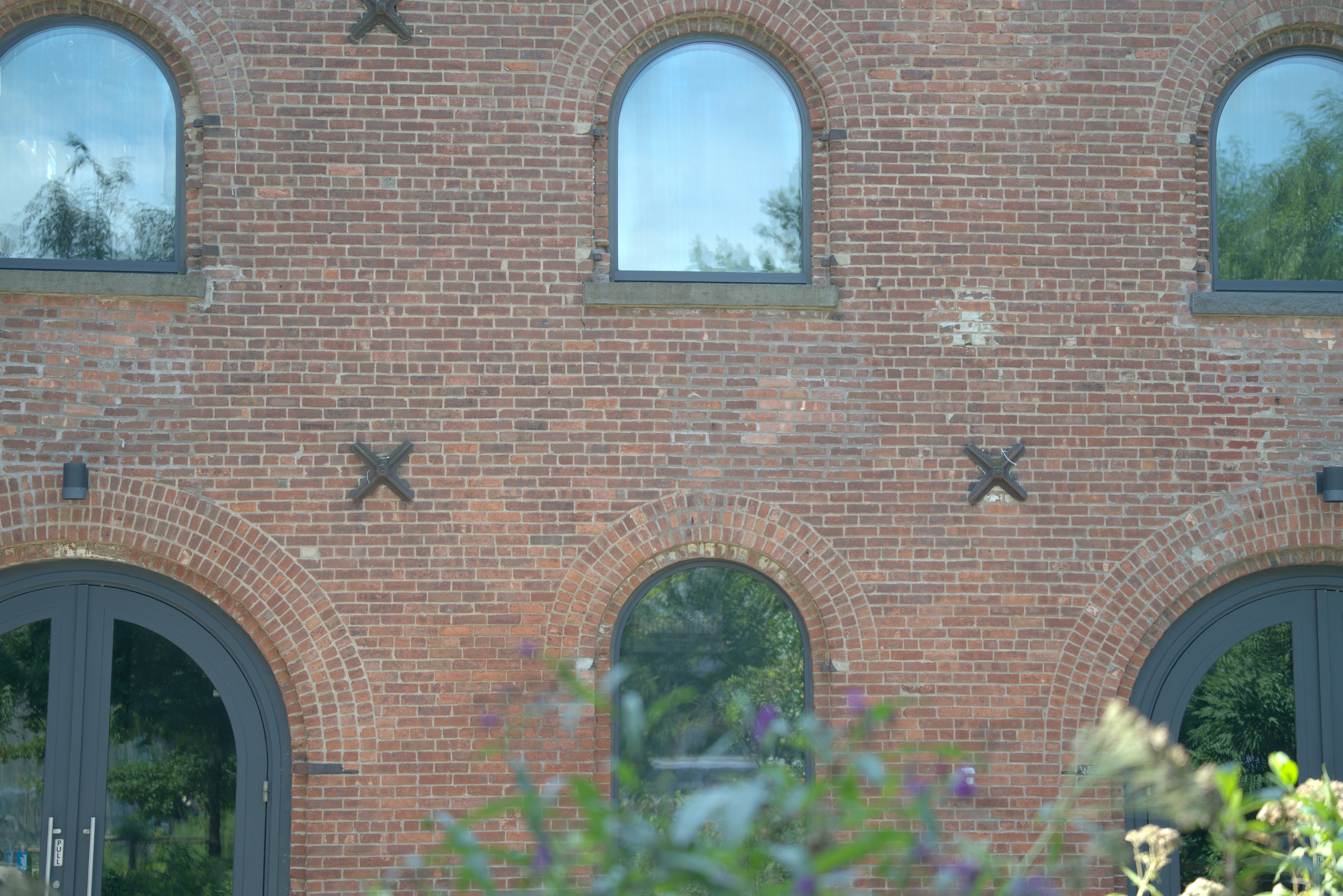 Brick Facade with Arched Windows and Subtle Flora Foreground