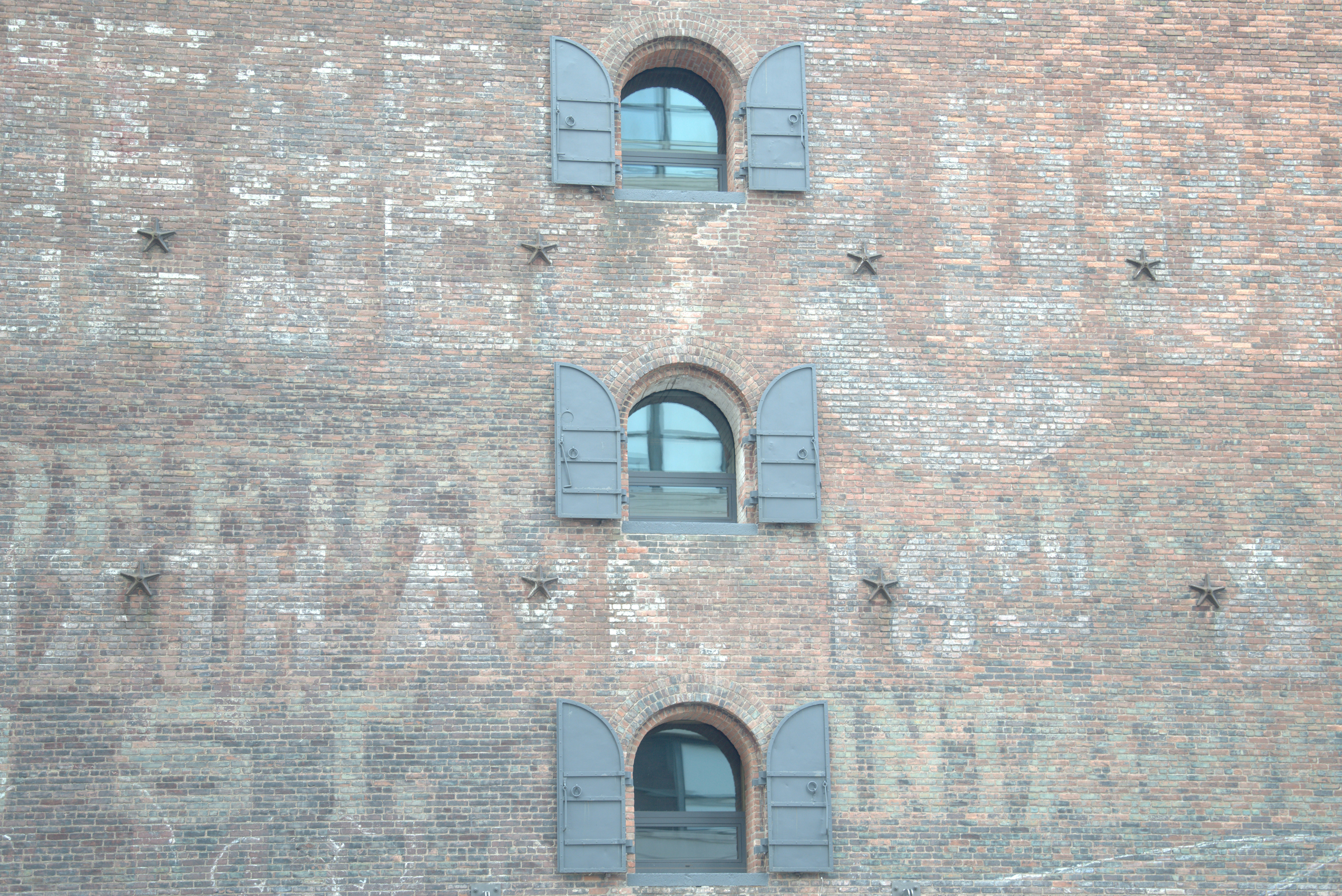 Three Shuttered Windows on Weathered Brick Facade