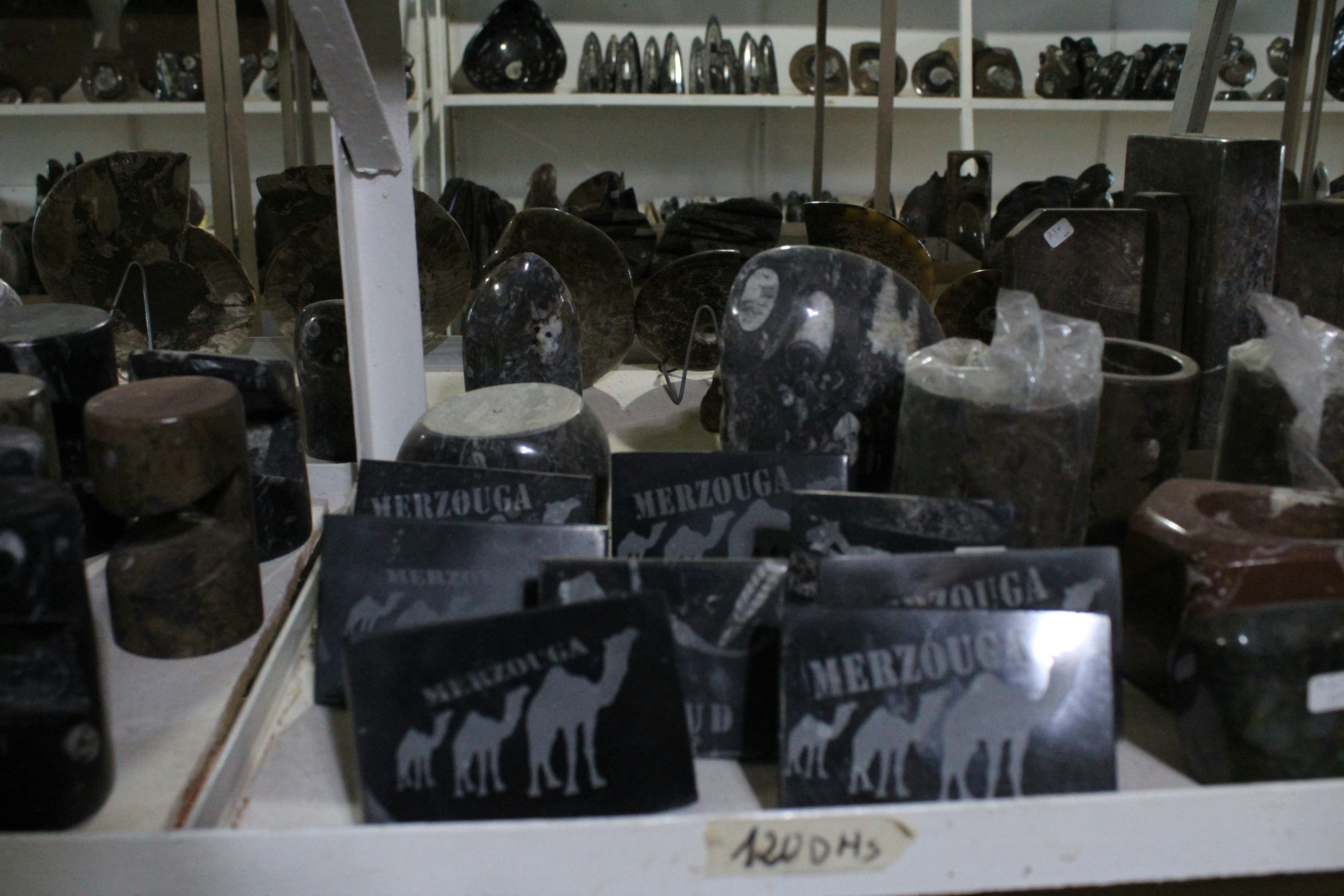 Dusty display of Merzouga keepsakes in a shadowed shop aisle