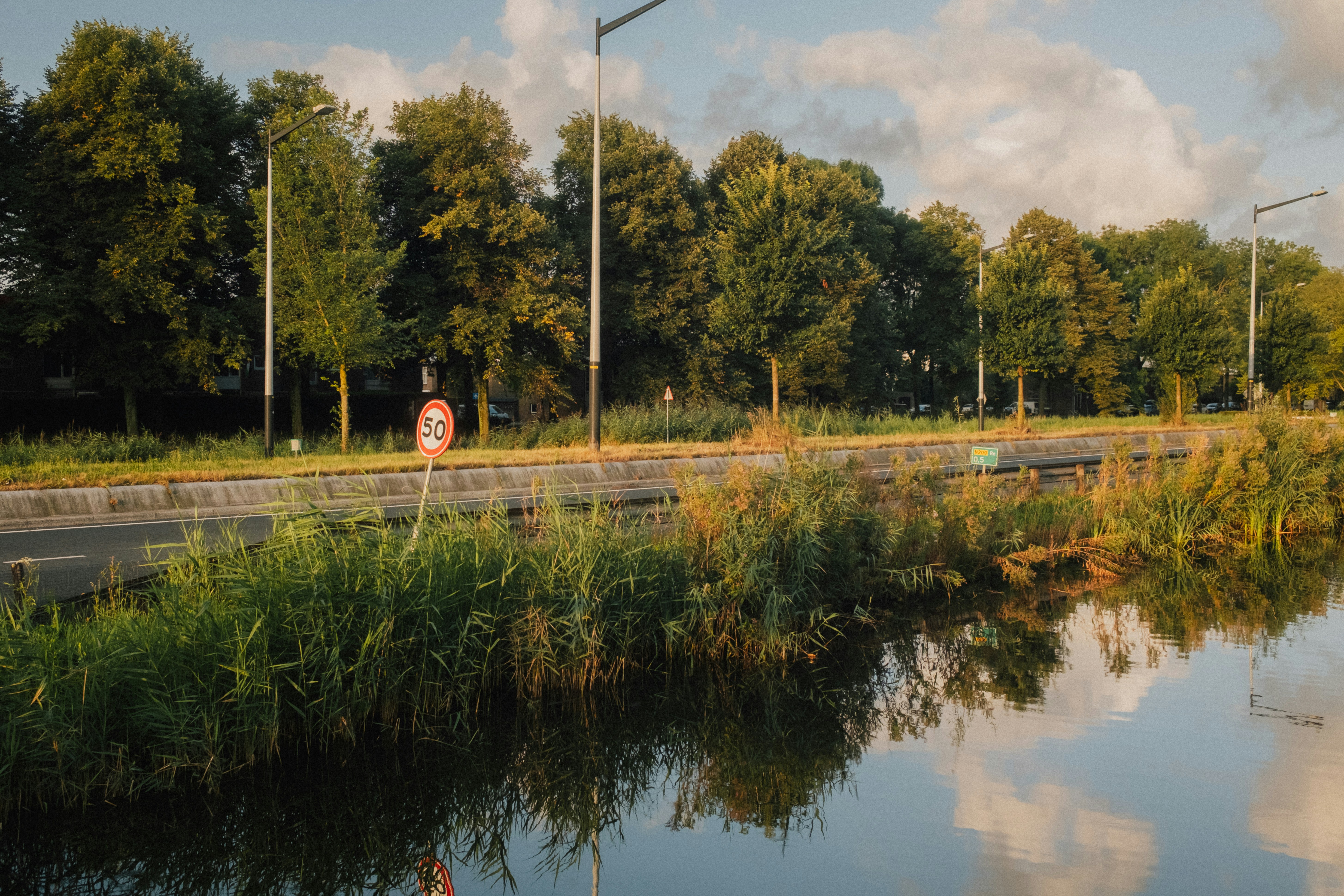 Quiet riverside road with a mirrored sky