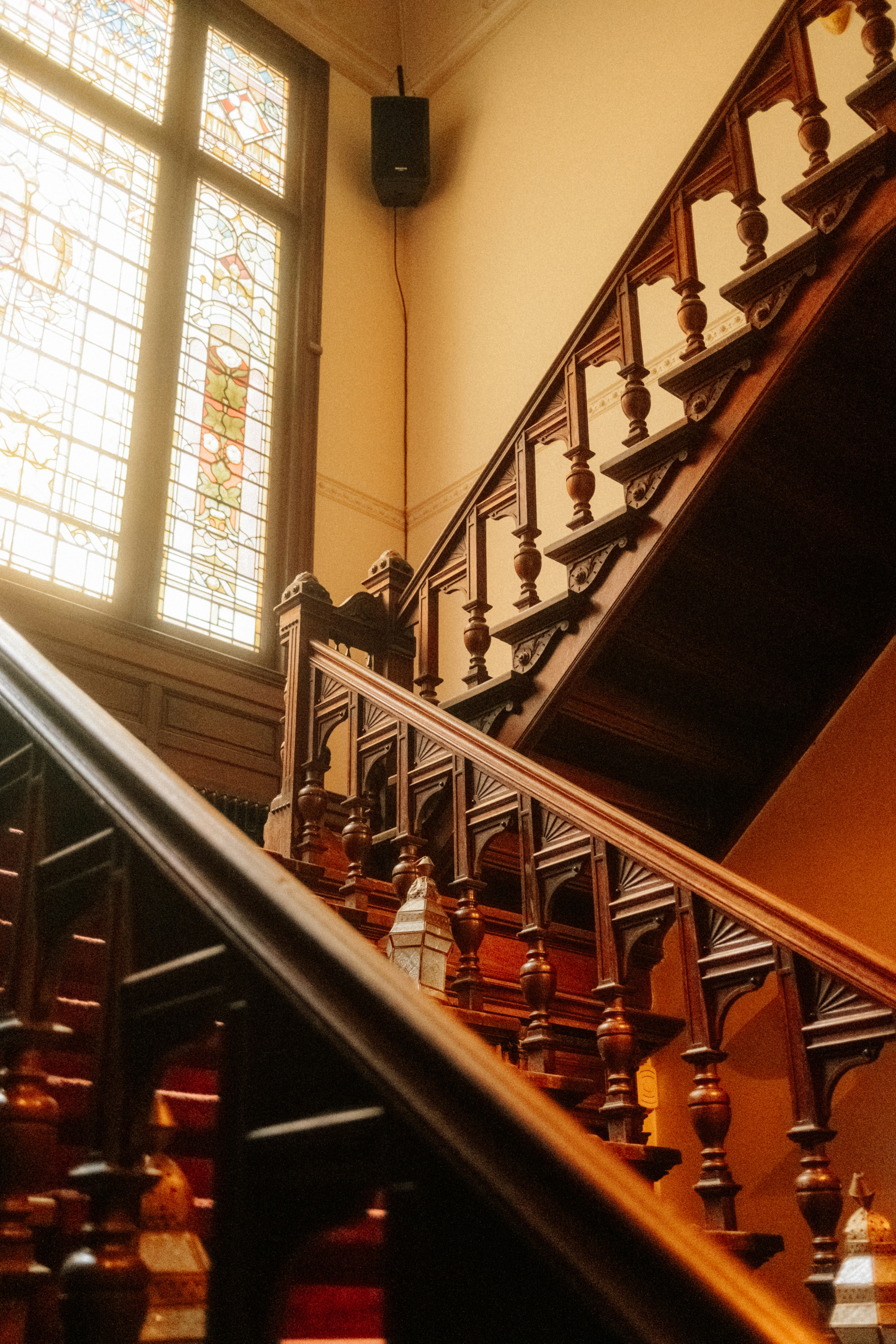 Stairway to Warm Light: A Vintage Interior’s Wooden Riser and Stained Glass