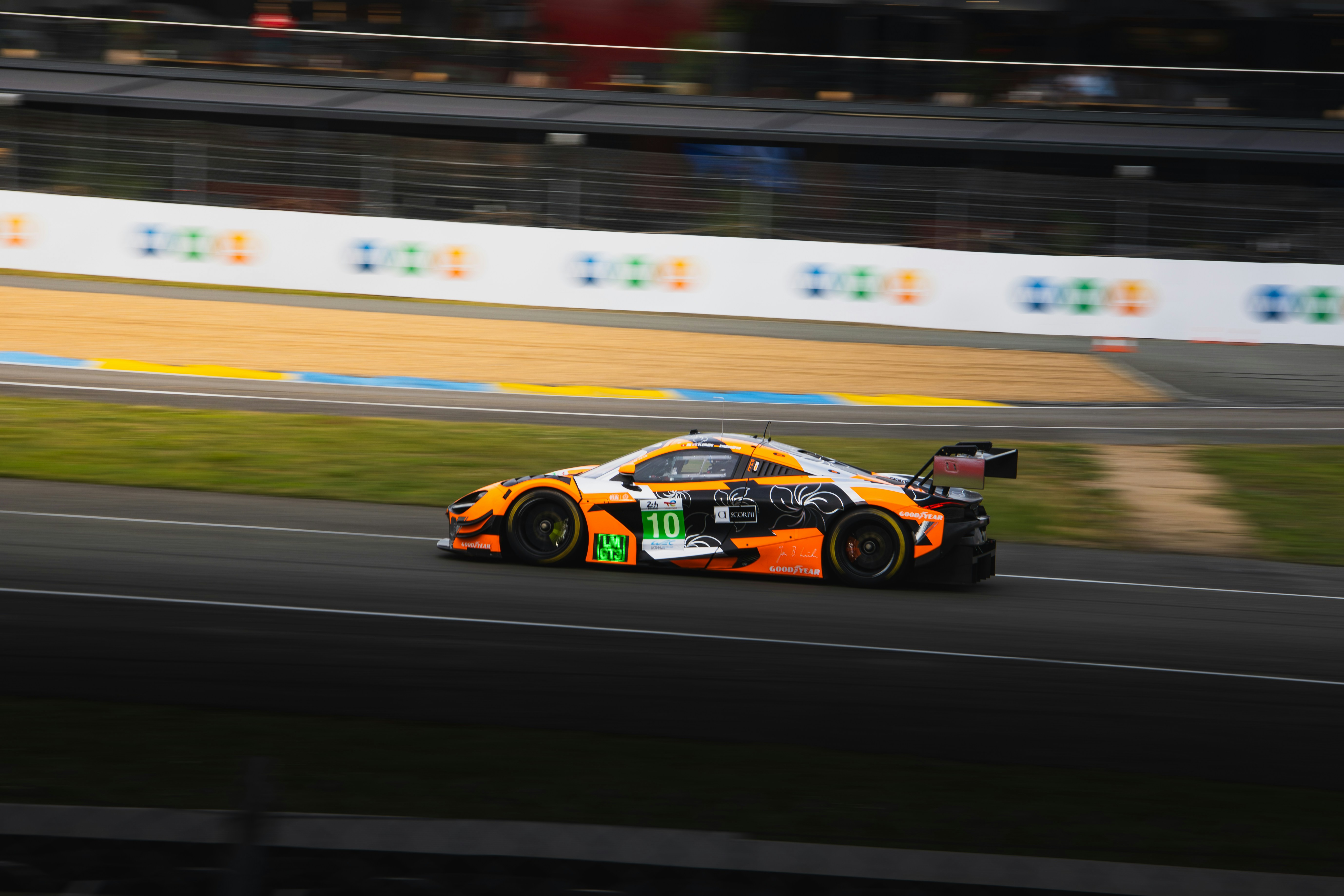 Orange Racecar in Motion on a Track
