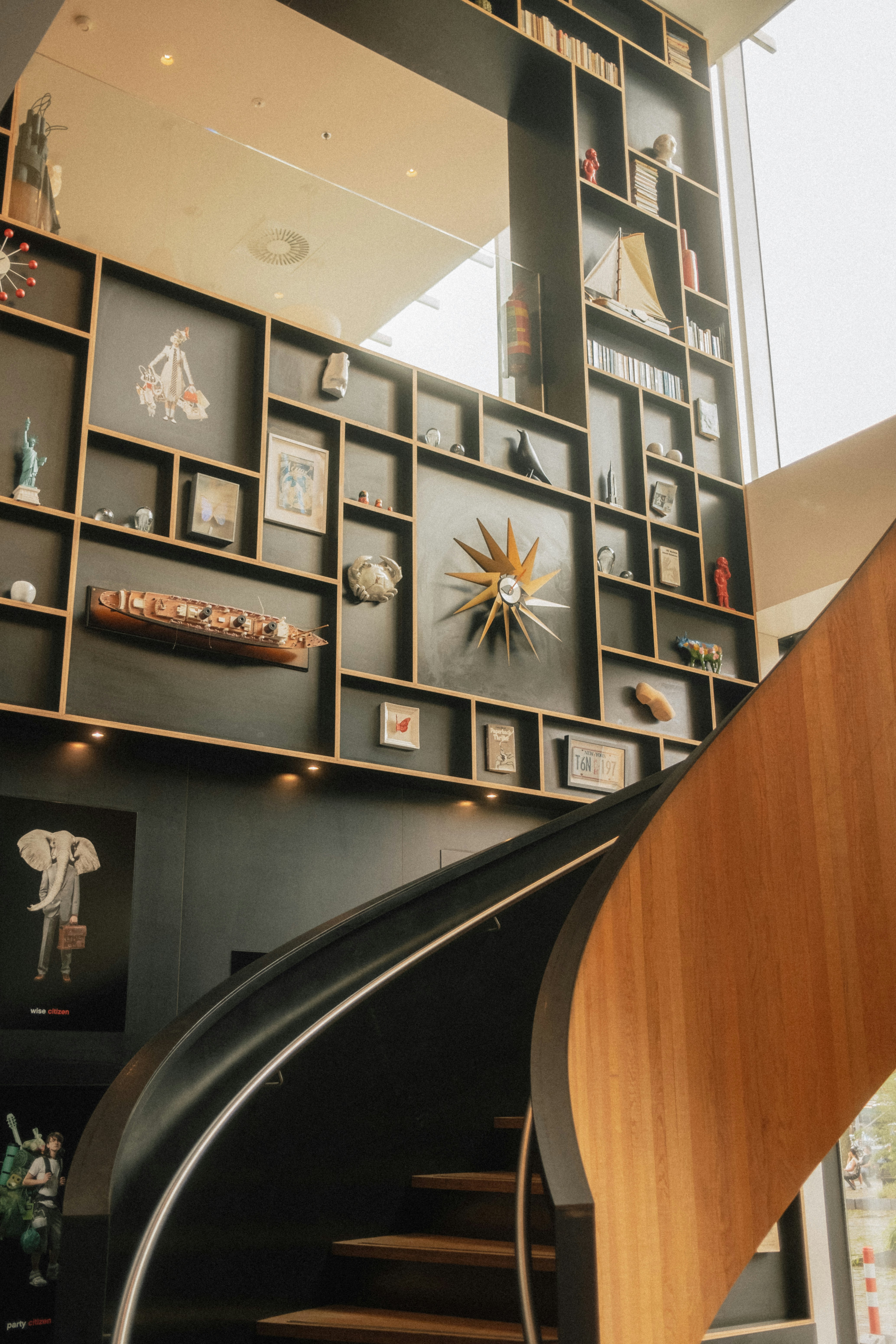 Interior gallery staircase: geometric shelves, mid-left clock sunburst centerpiece