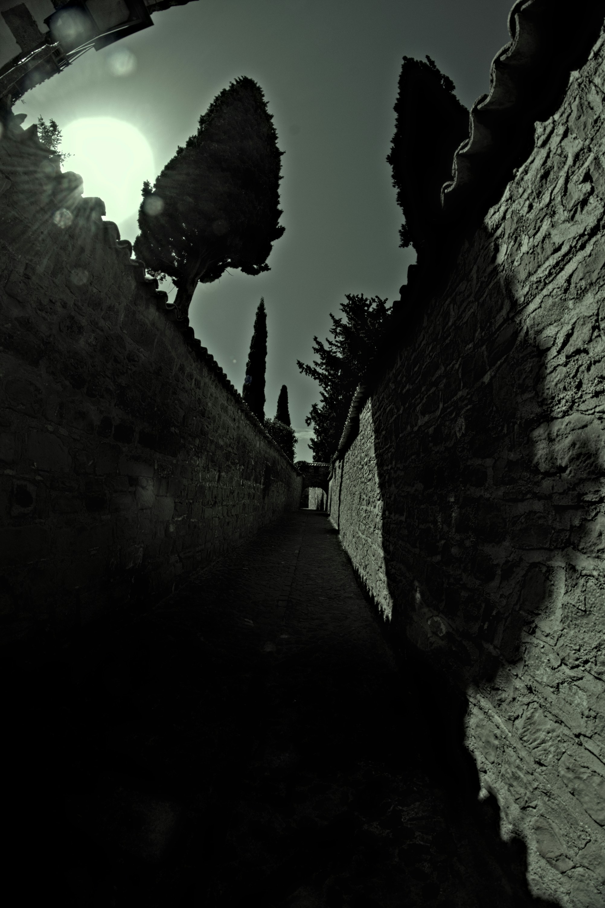 Sunlit Gloom: A Narrow Stone Corridor Reaching Toward a Distant Gate
