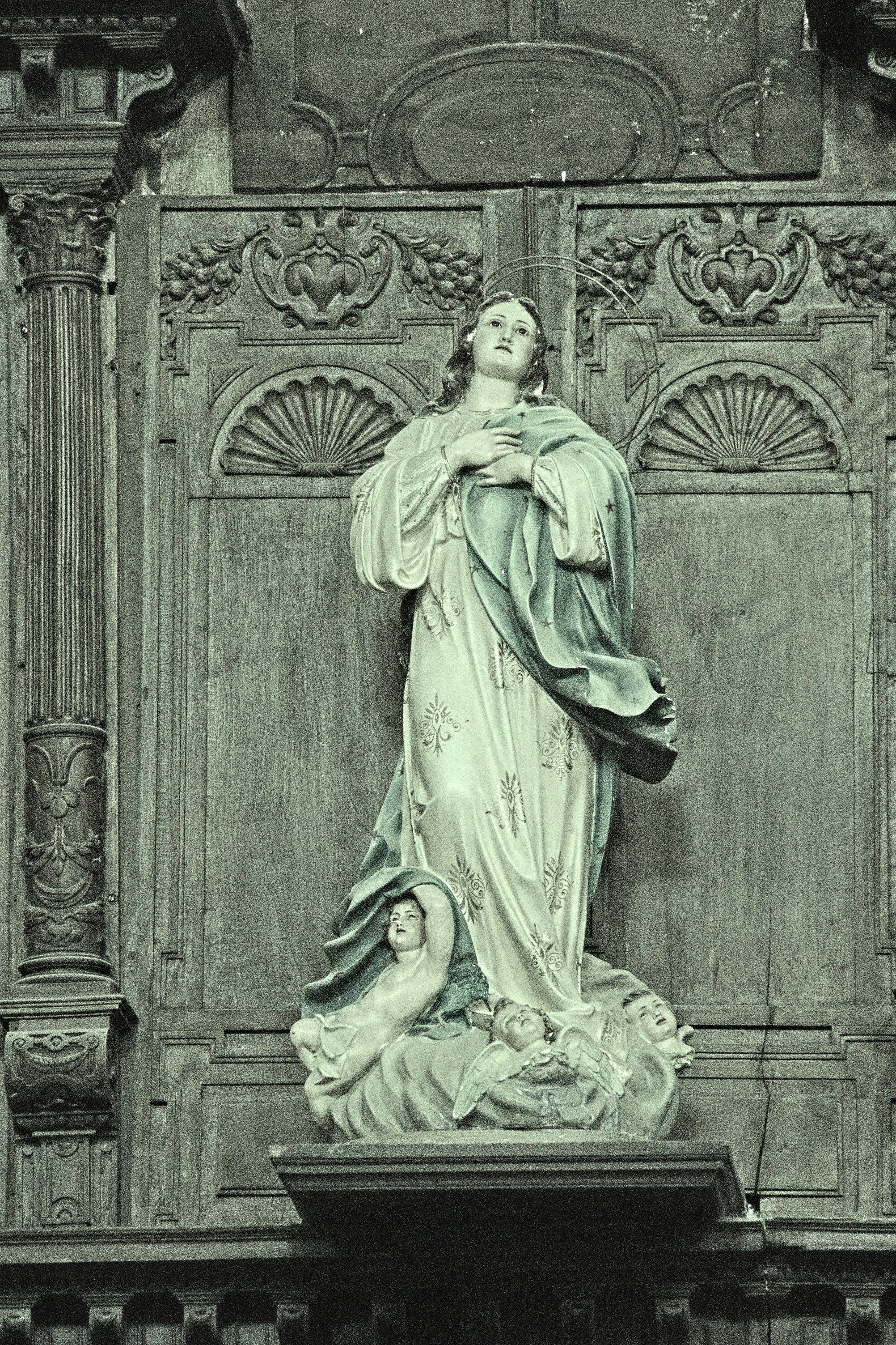 Silent Guardian in Stone: A Reverent Statue Amid Ornate Carvings