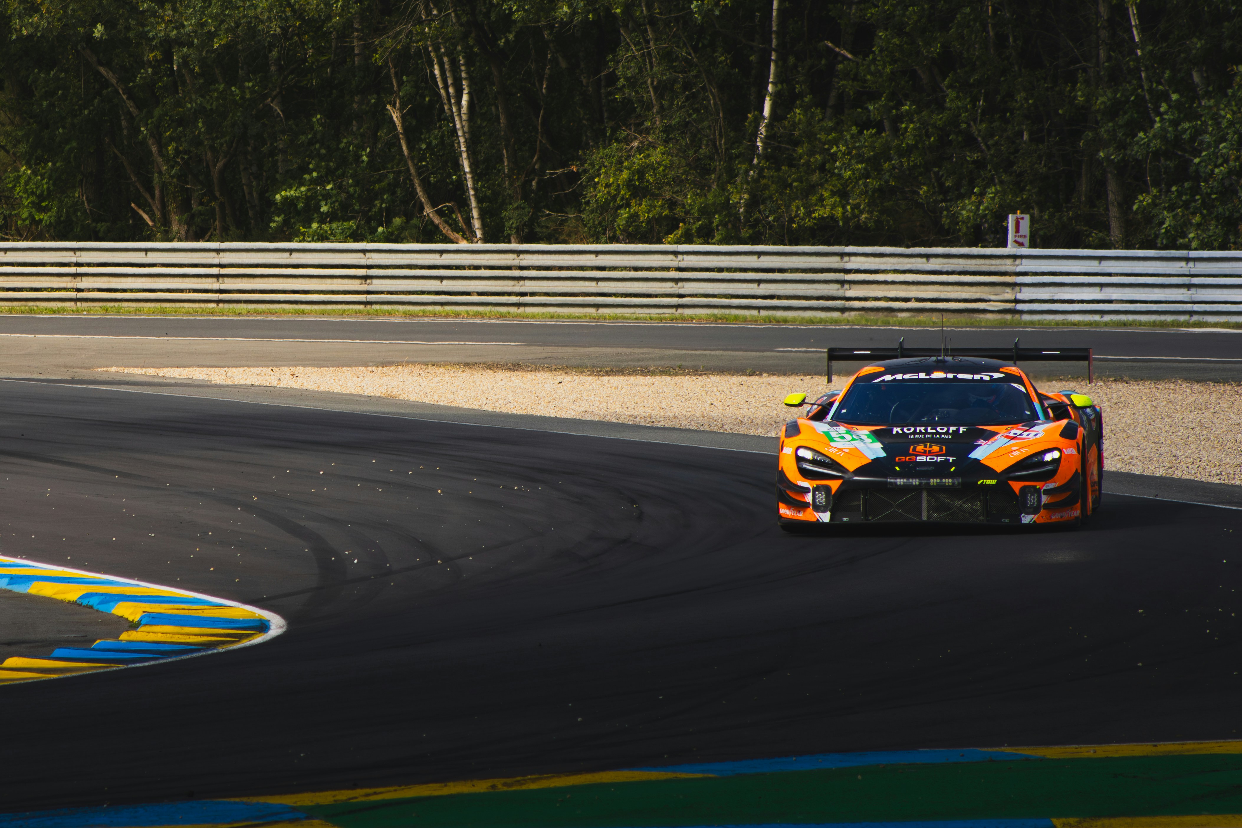 Orange racer rounding the bend on a sunlit circuit