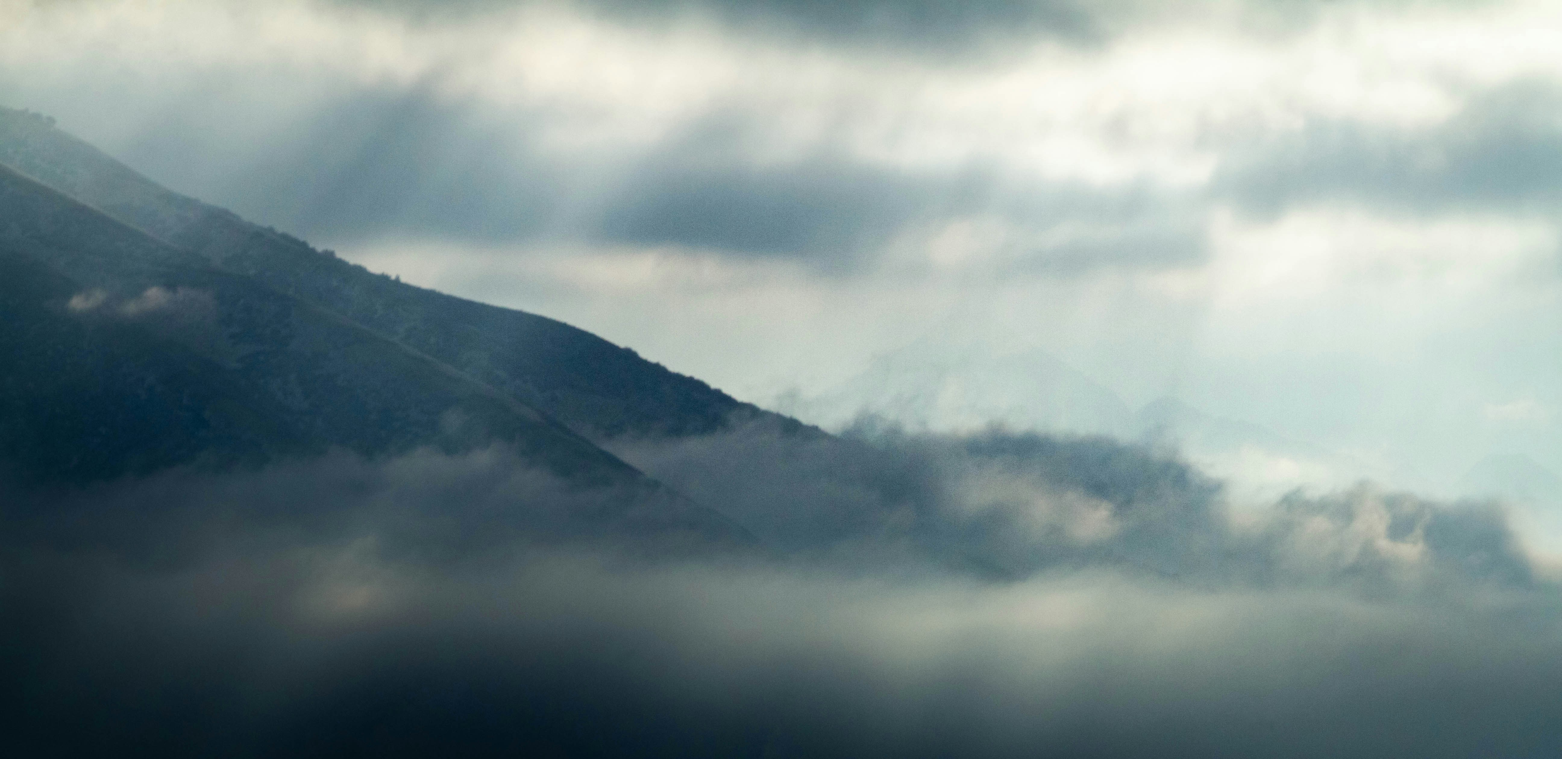 Misty Ridge: Sunlight Piercing Through Veiled Peaks