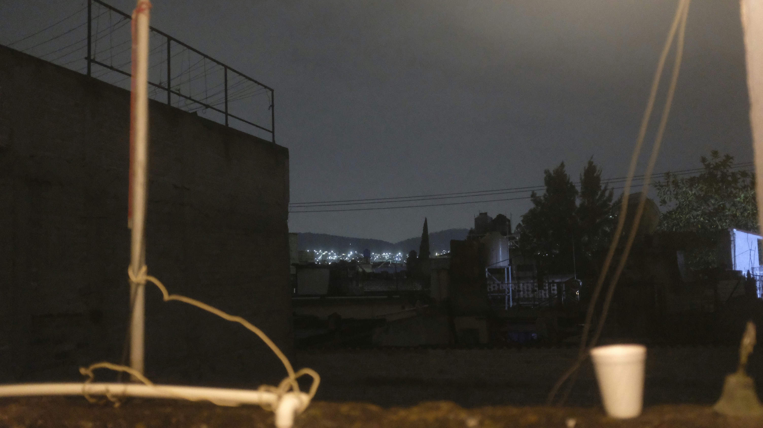 Night on the Rooftop: Quiet City Lights Behind a Fringe of Fence