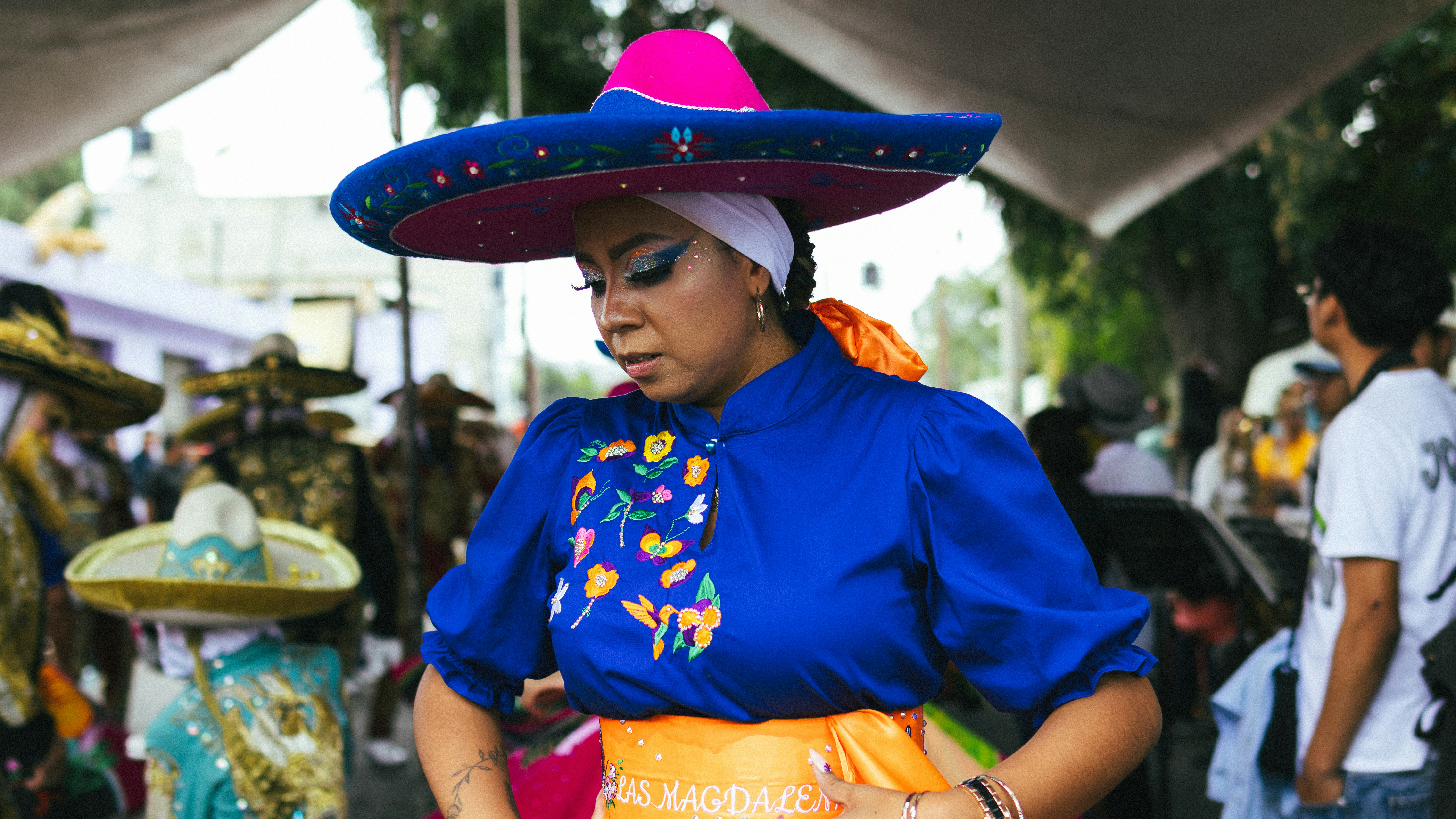 Colorful Fiesta Attire: A Woman in a Bright Blue Dress at a Market Parade