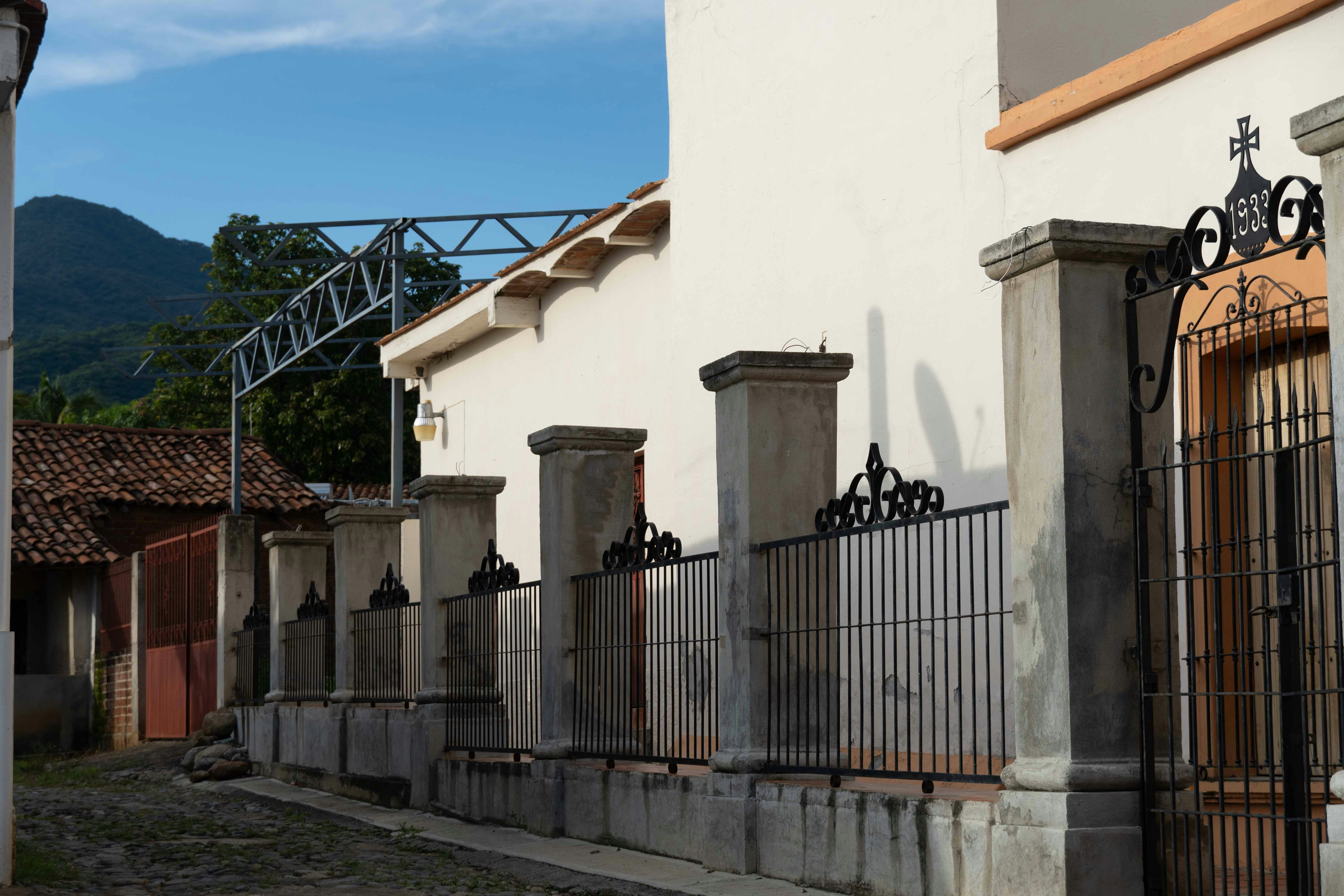 Sunlit Curbside Fence: Quiet Street Scene