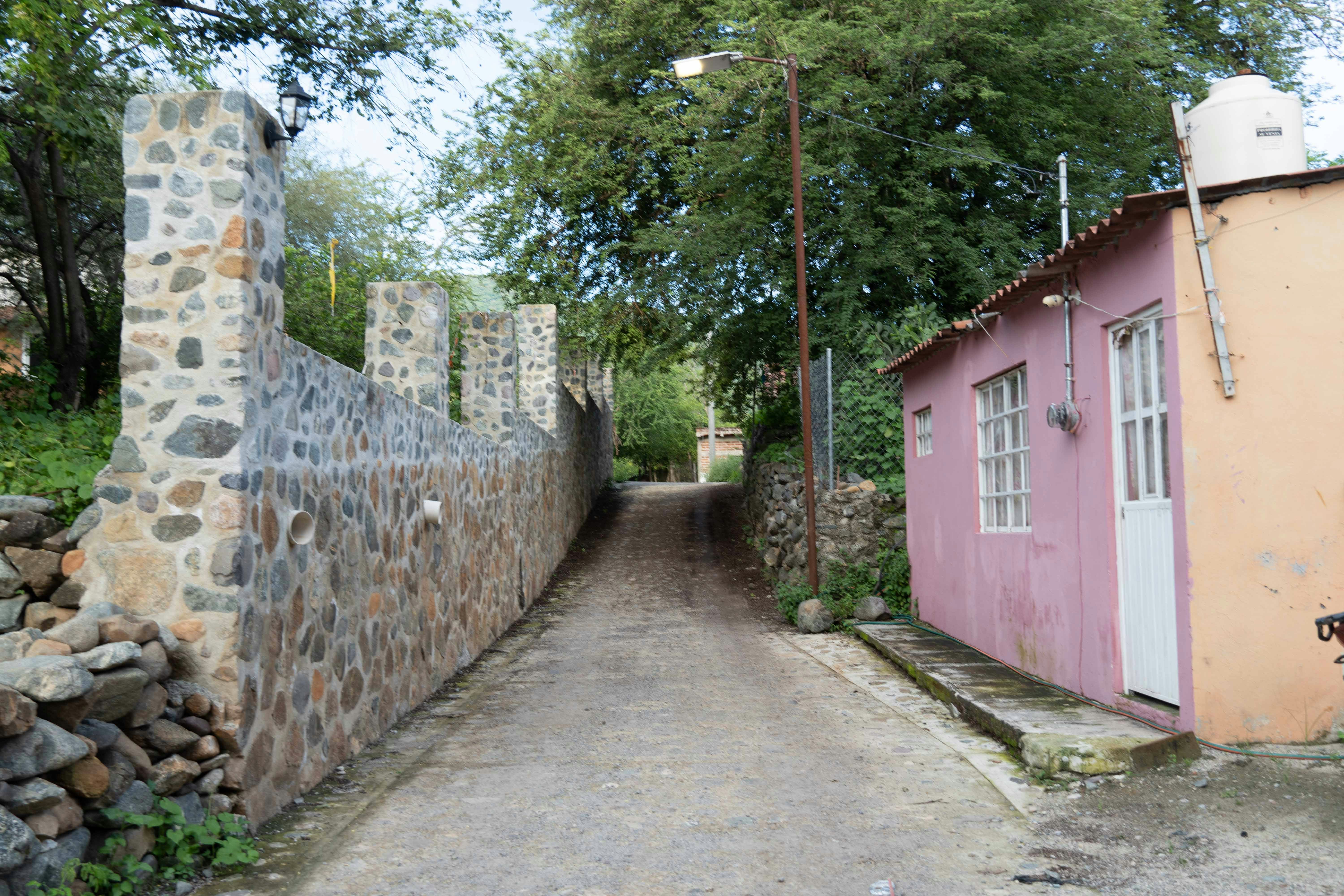 Quiet Lane Between Stone Wall and Pink House