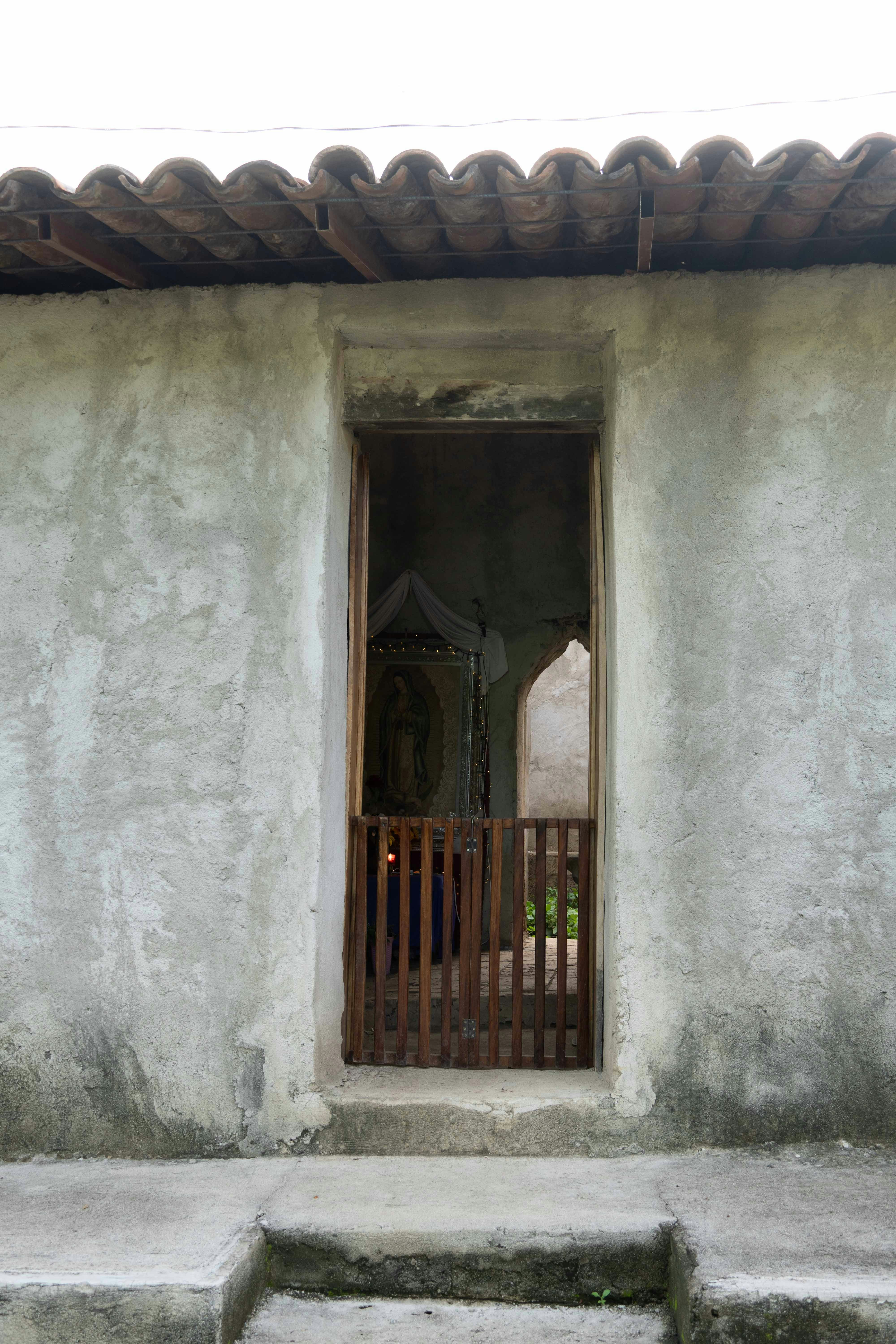 Through the Rustic Door: A Quiet Shrine Seen Beyond a Weathered Barrier