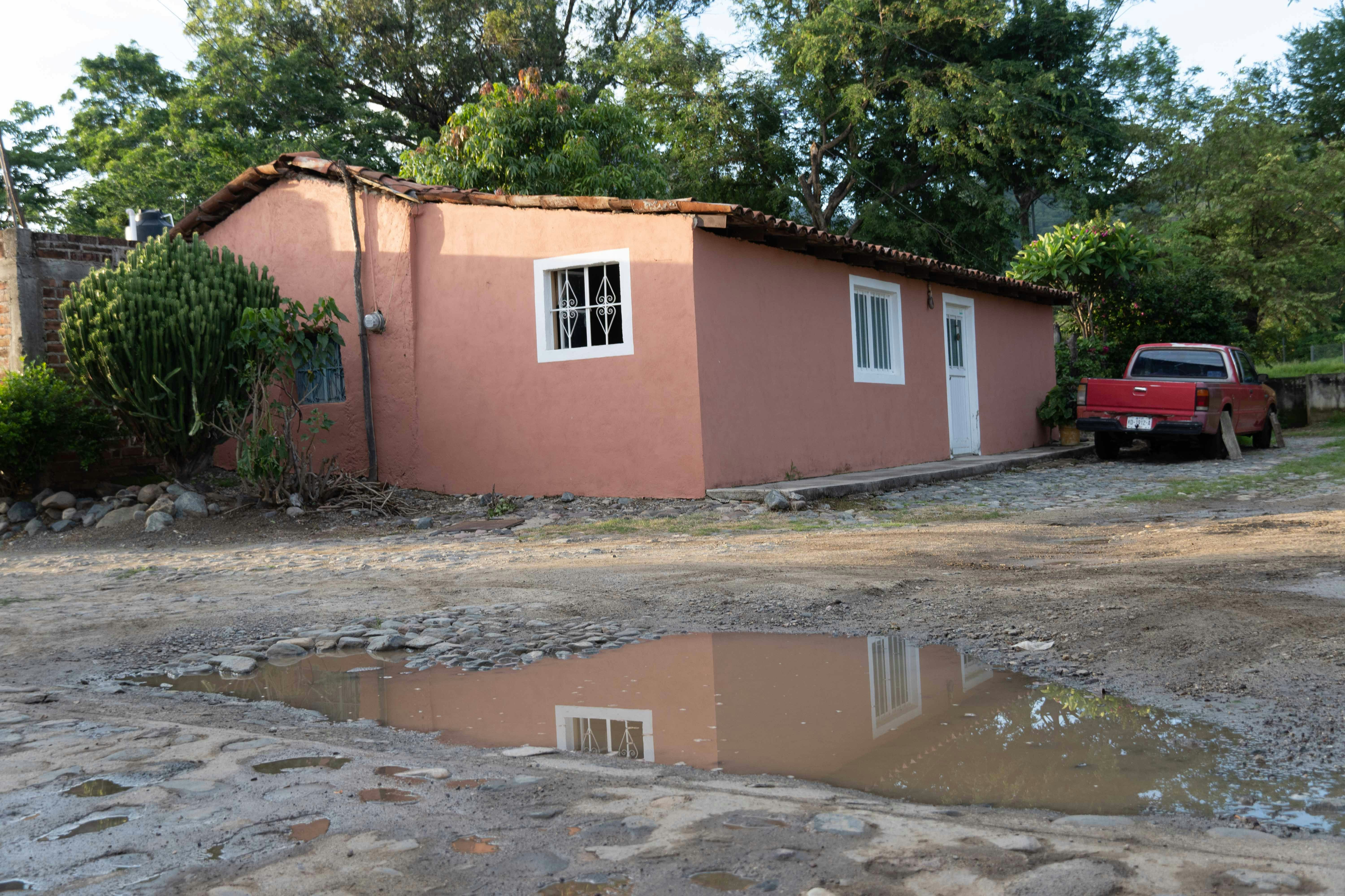 A pink house with a red tiled roof beside a red pickup truck