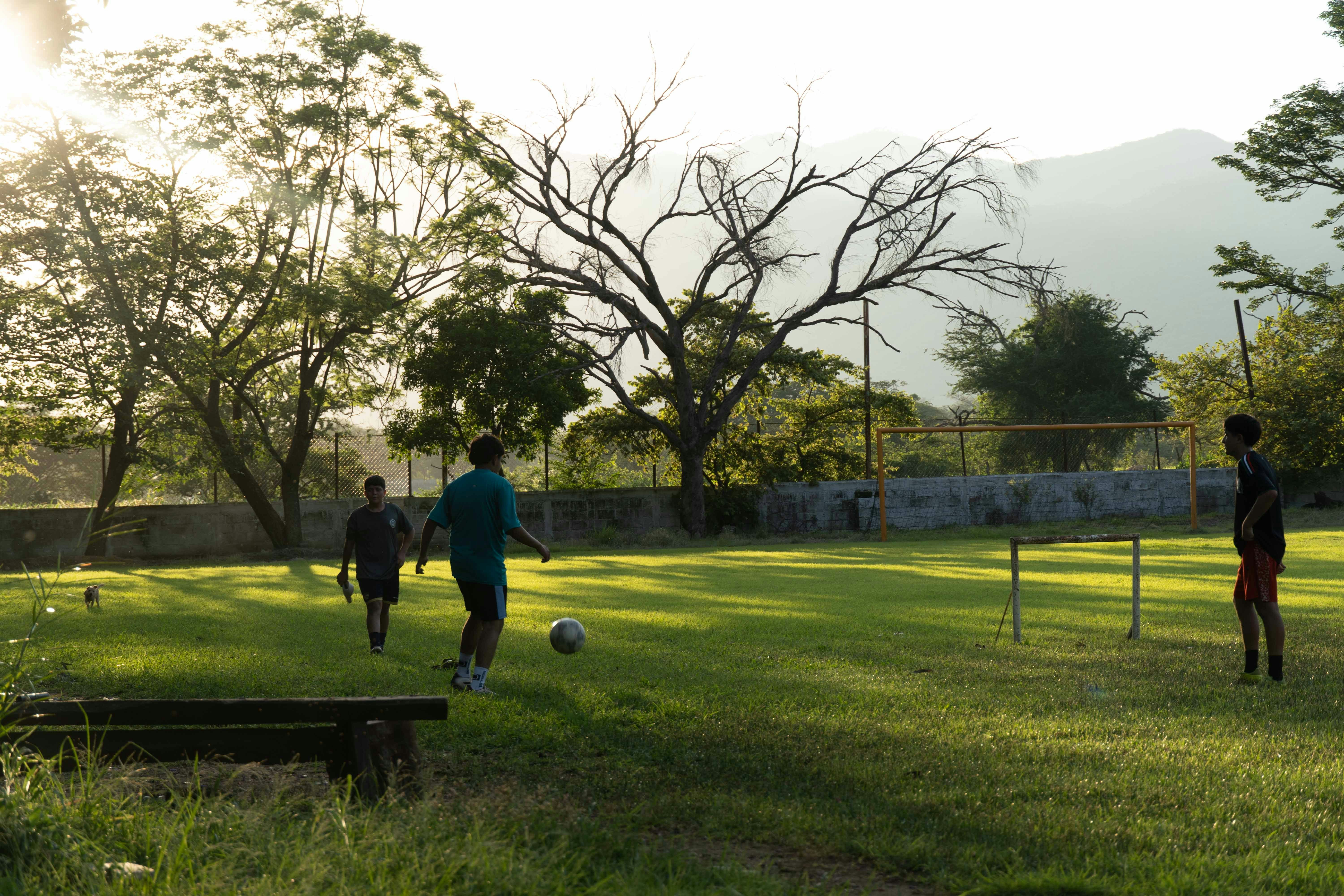 Midfield Kick: Players Rally on a Sunlit Park Field