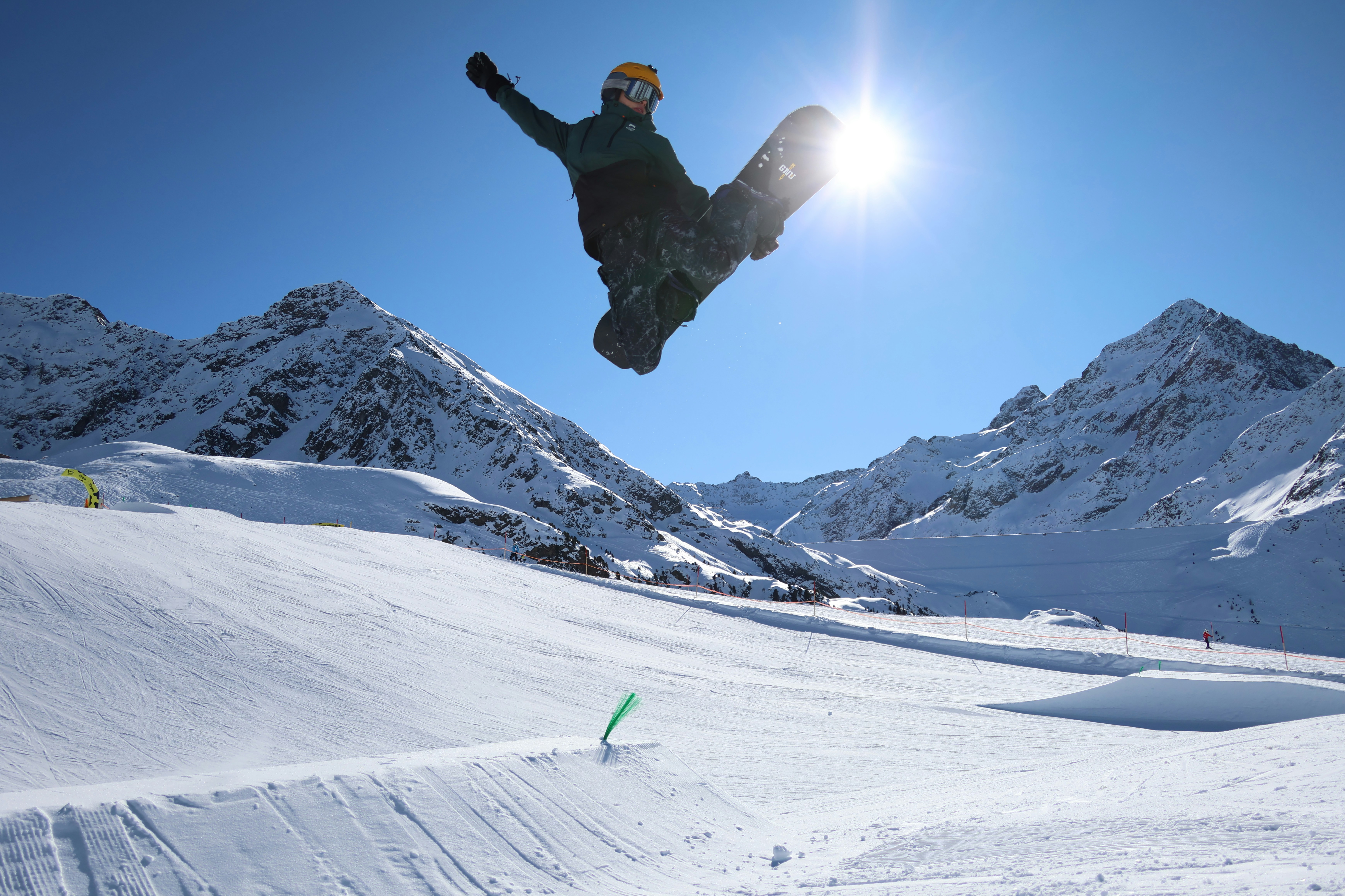 High-Impact Aerial: Snowboarder Soars Against Alpine Crest
