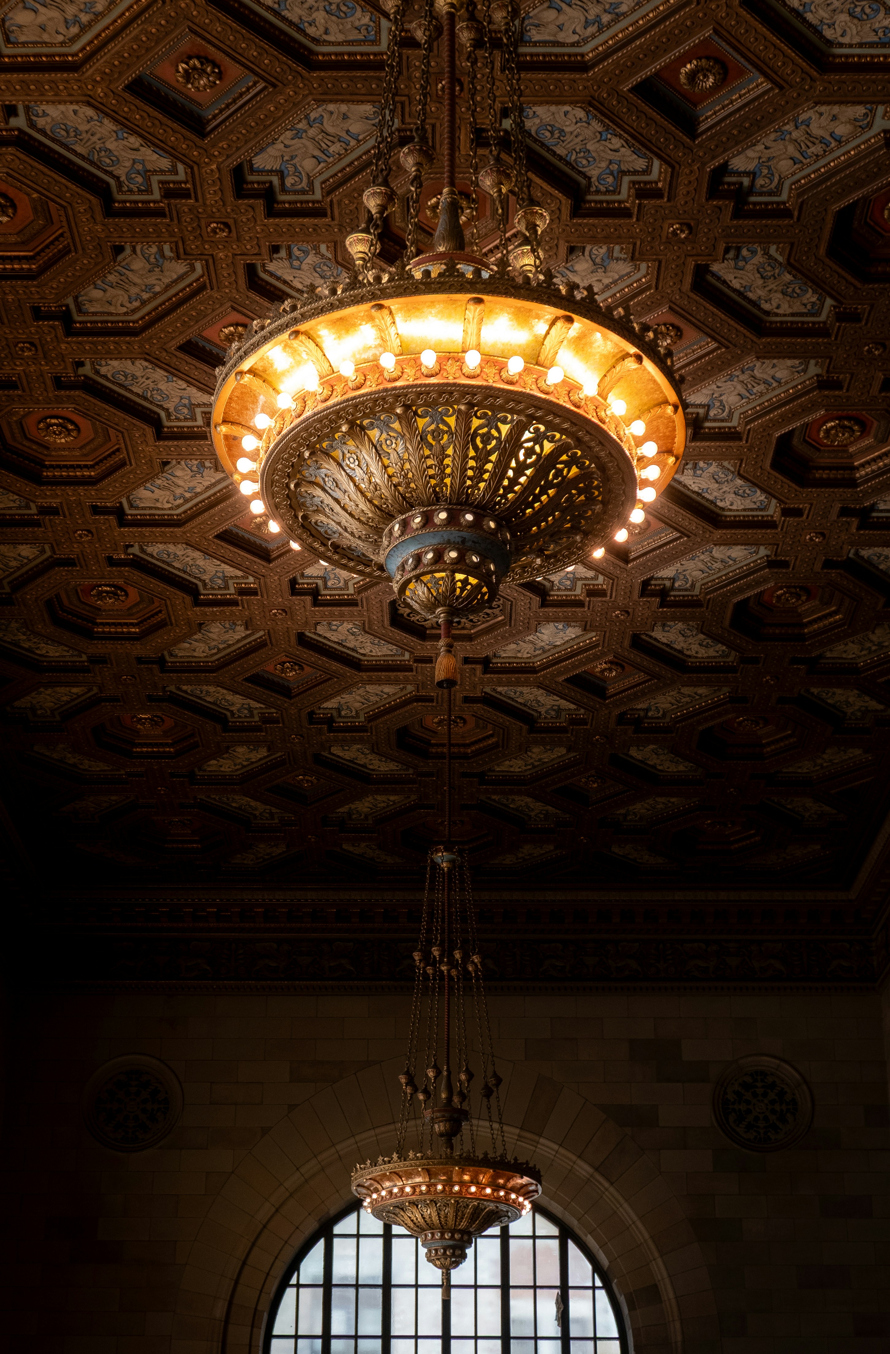 Golden Chandelier Glow Beneath Ornate Coffered Ceiling