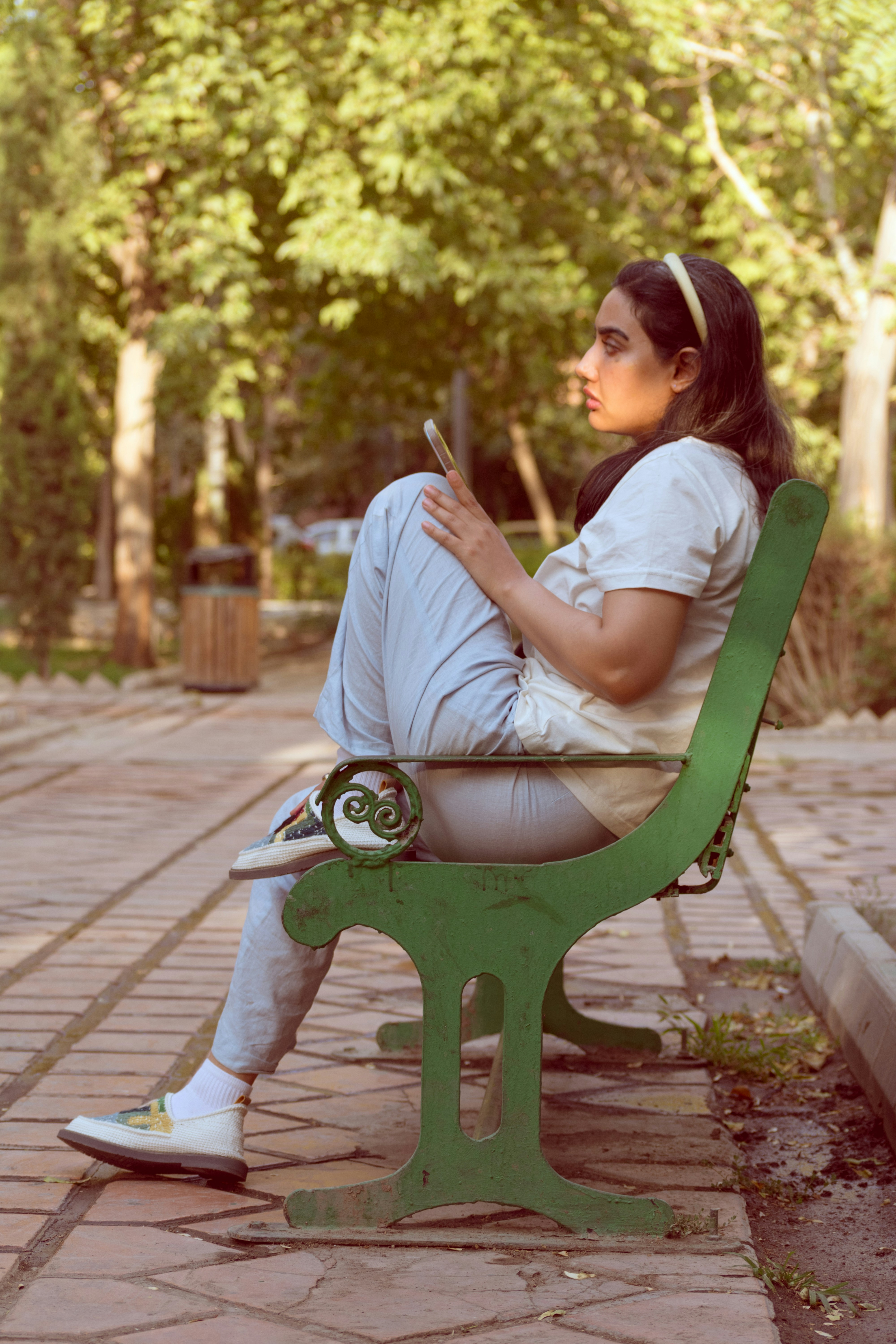 Portrait in a Quiet Park: a Woman in a White Outfit Reading on a Green Bench