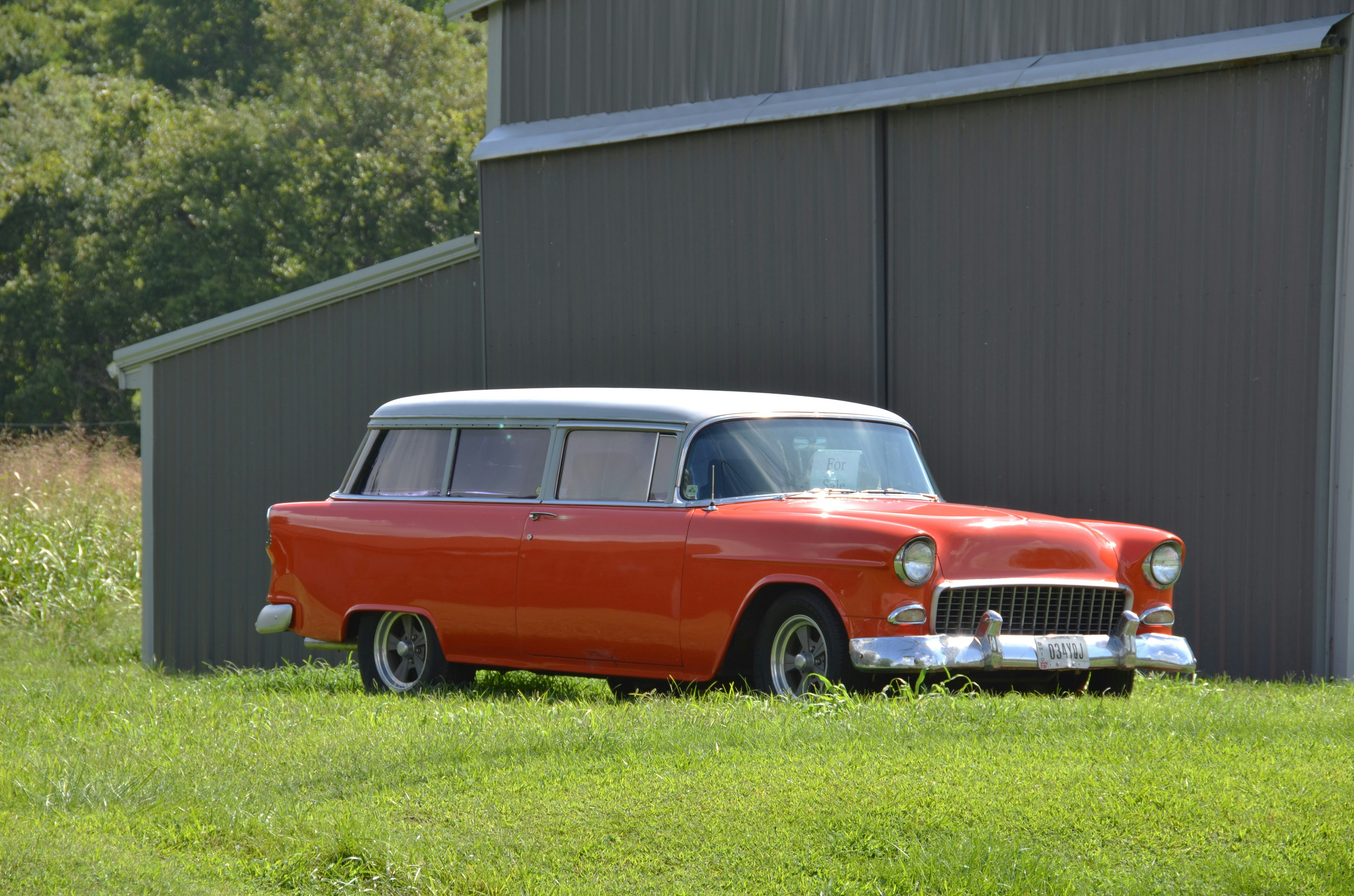 Red vintage wagon resting beside a gray barn under sunlit summer skies