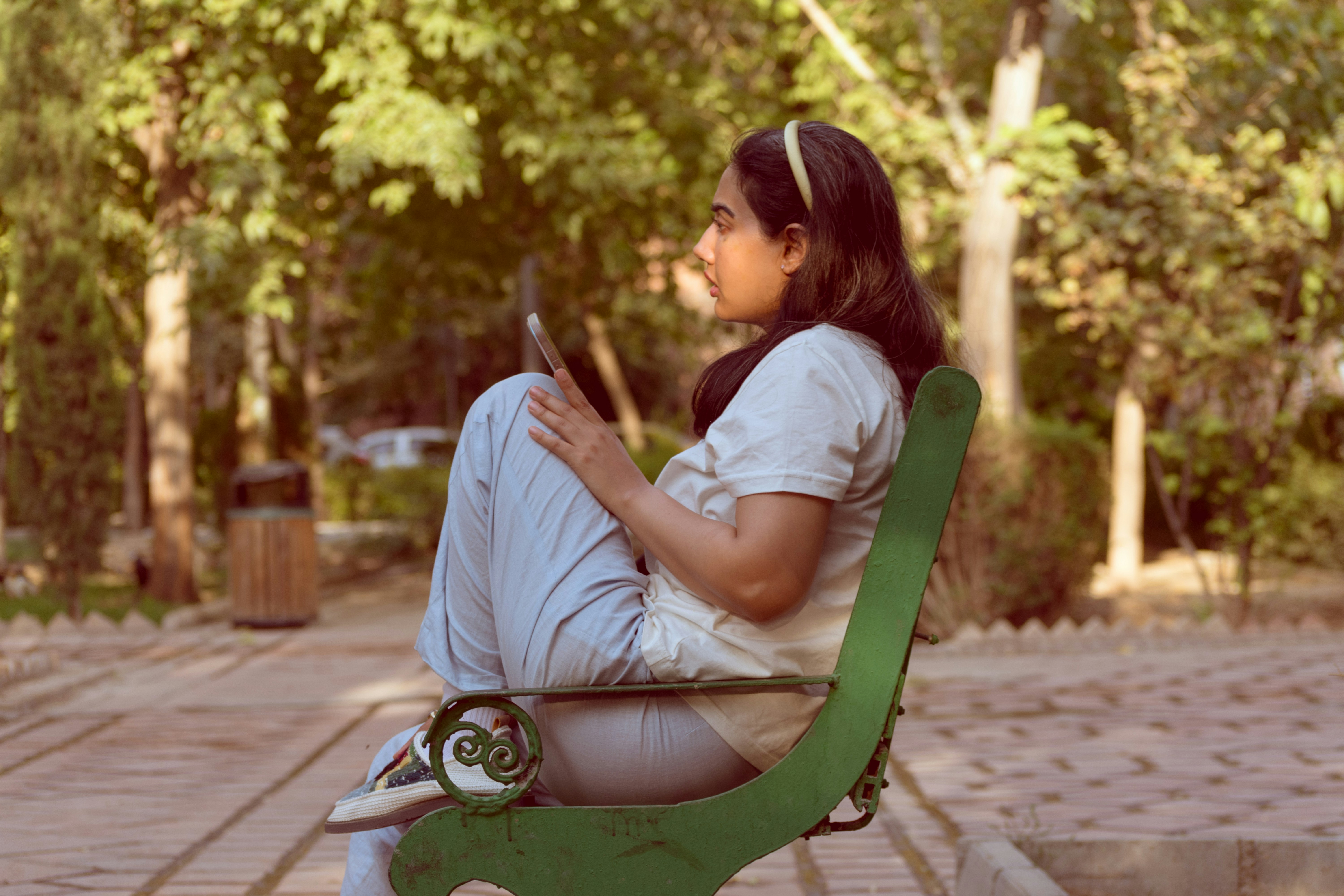 Relaxed Portrait on a Park Bench: Focused Gaze and Tablet Glow