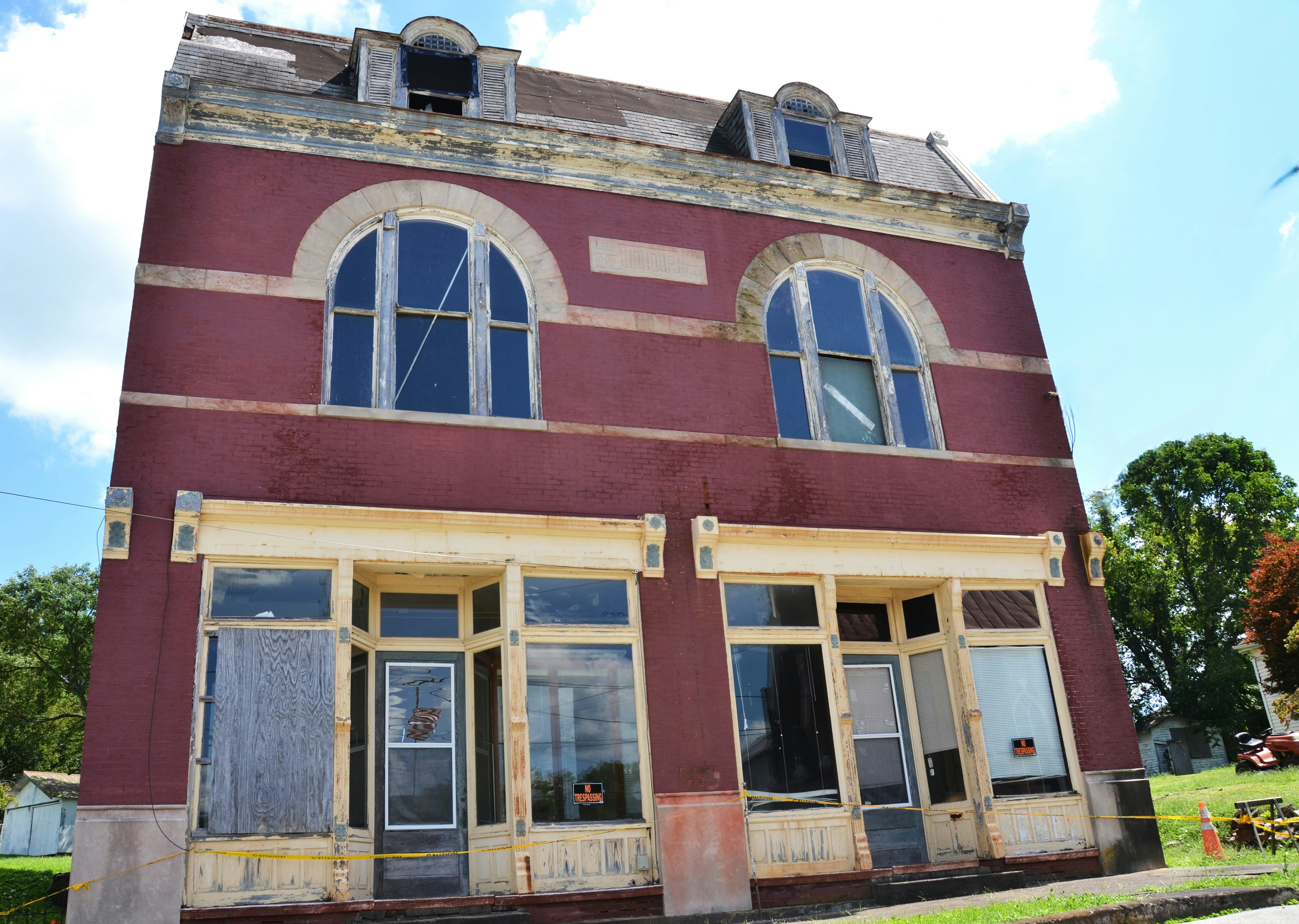 Forgotten Red Facade: An Abandoned Brick House with Tall Arched Windows