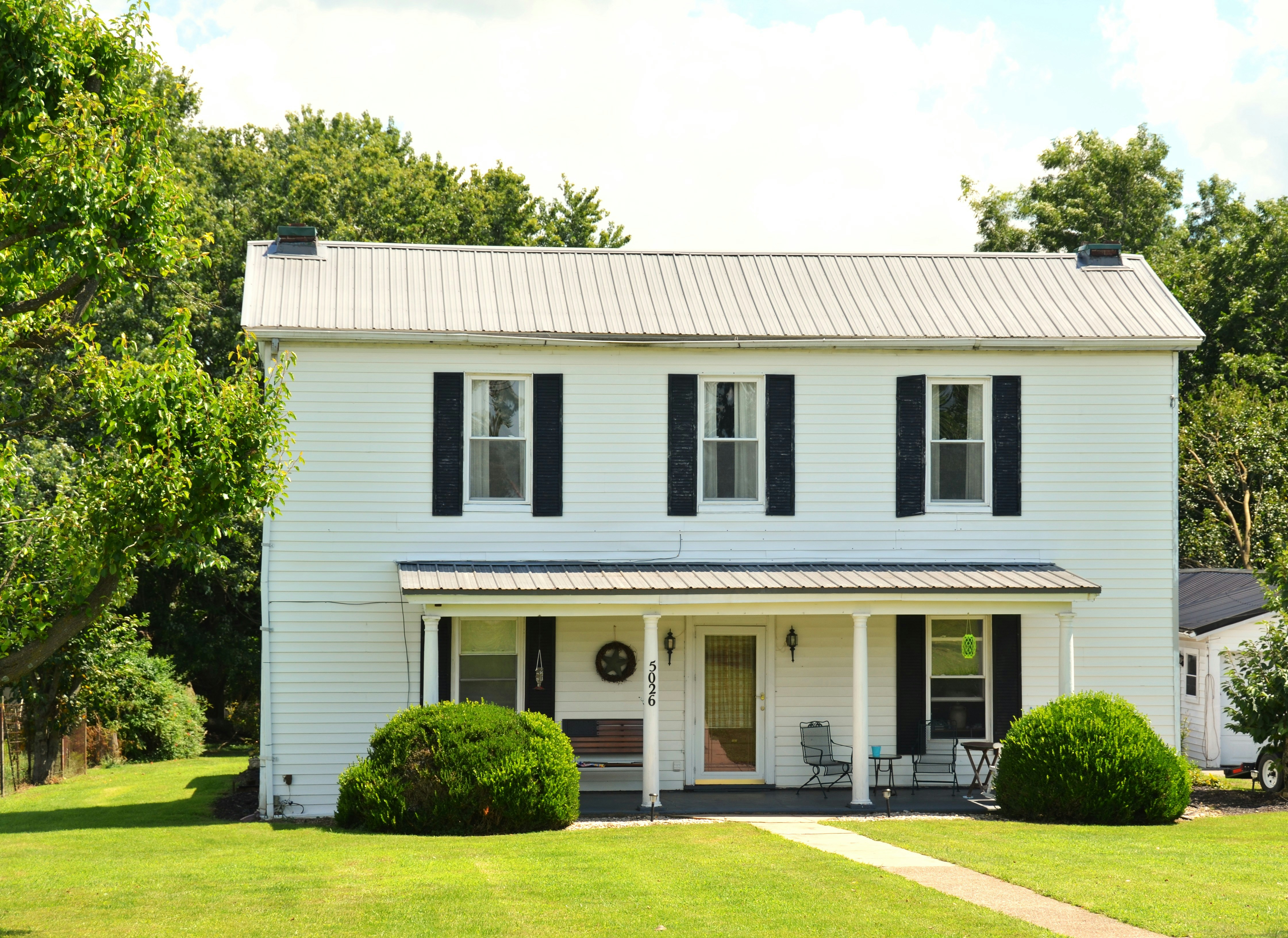 White Colonial House Surrounded by Greenery under Sunny Sky